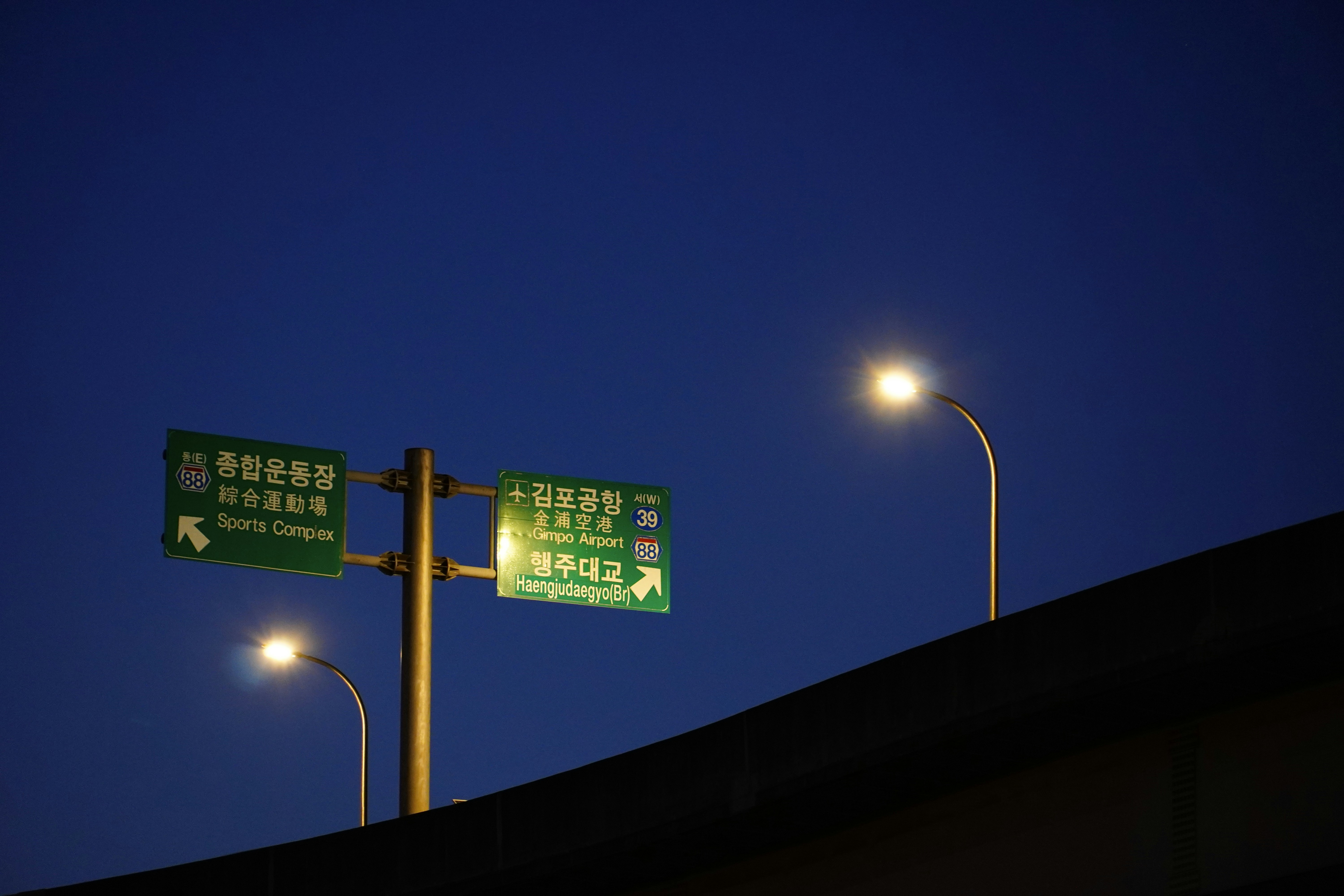 Green Direction at Dusk: Signposts Under a Quiet Urban Sky