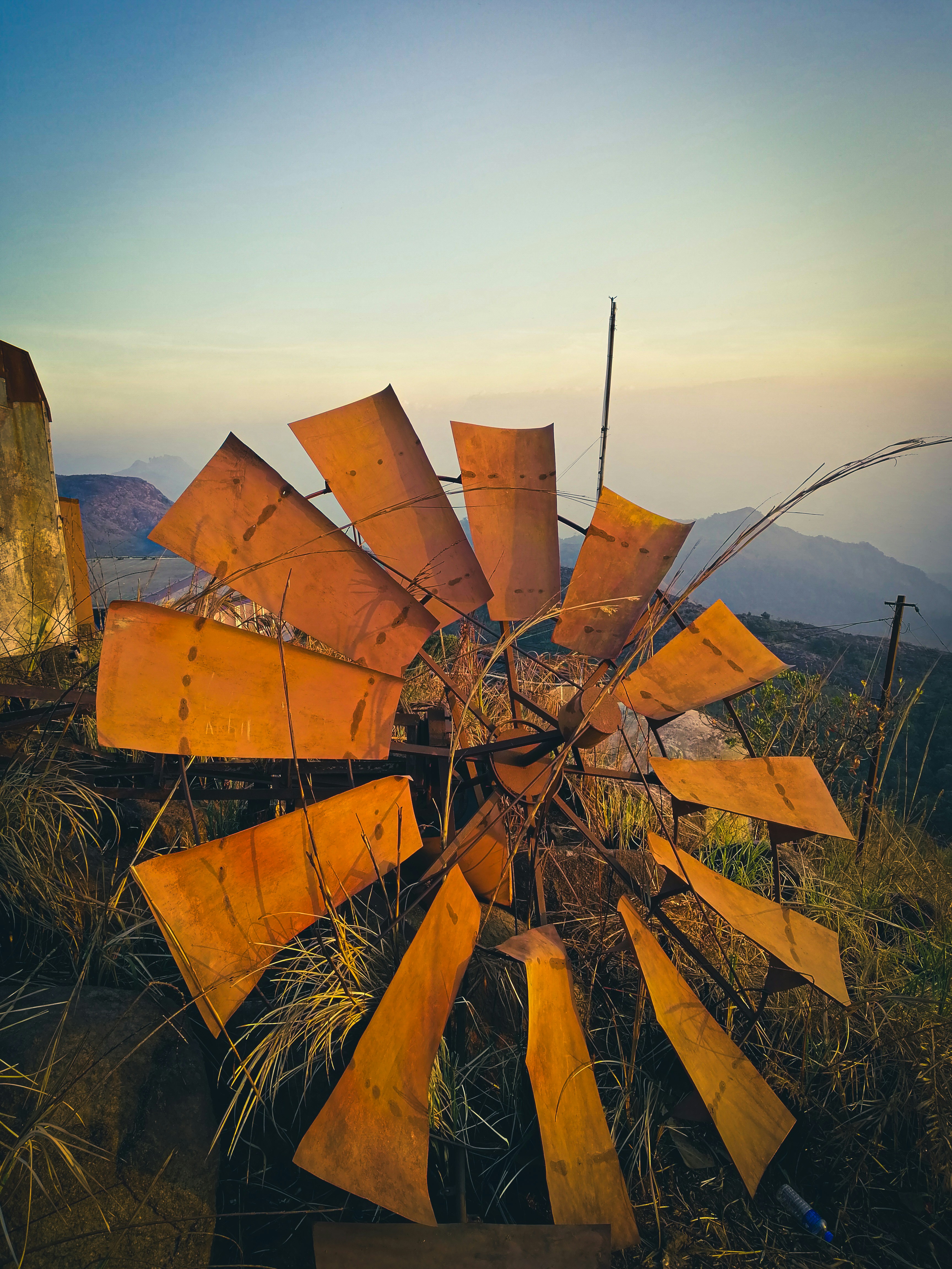 Crimson Pinwheels on a Hill: Rusted Windmill at Golden Hour