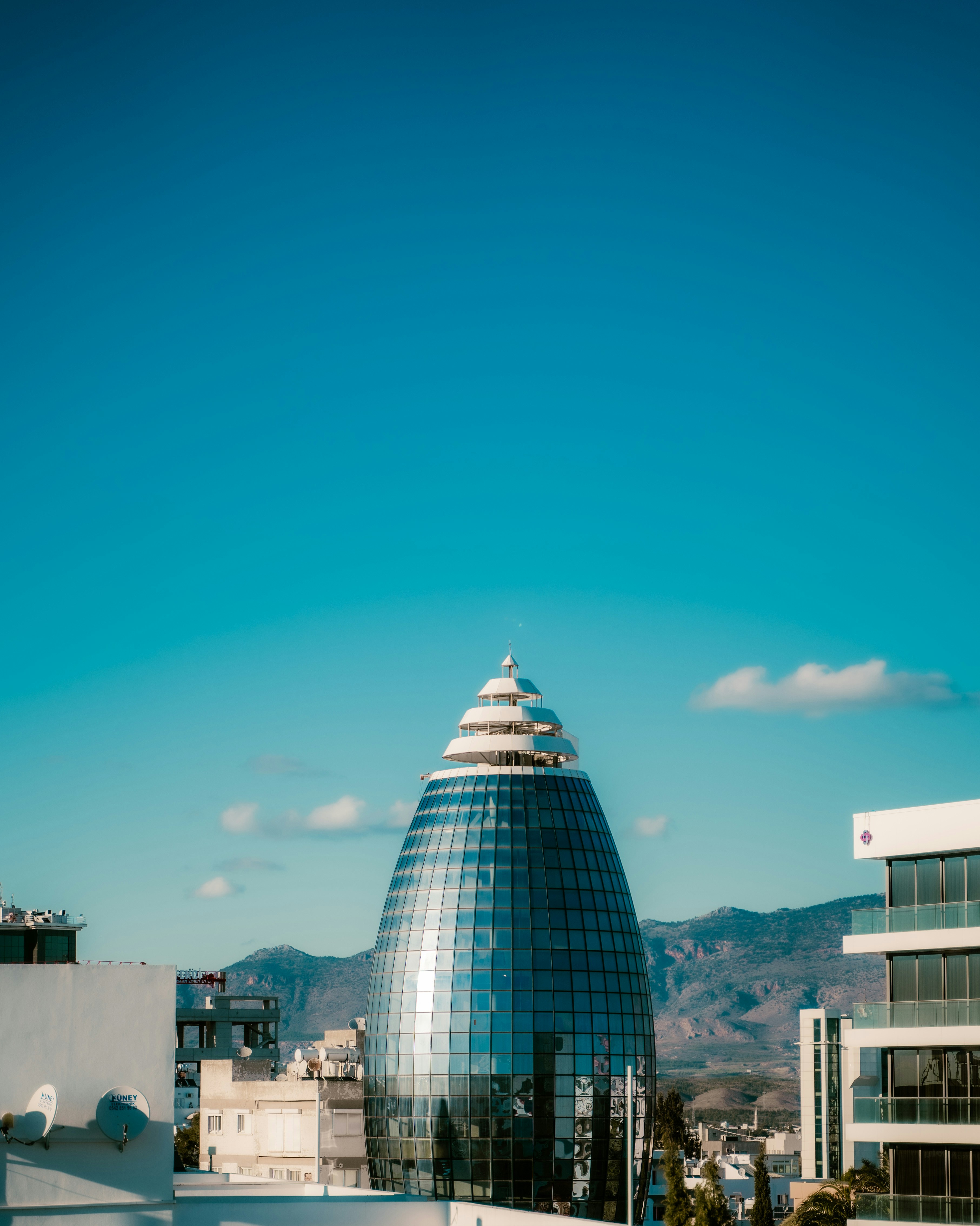 Egg-Shaped Glass Tower Rising Above a Desert-Backed Cityscape