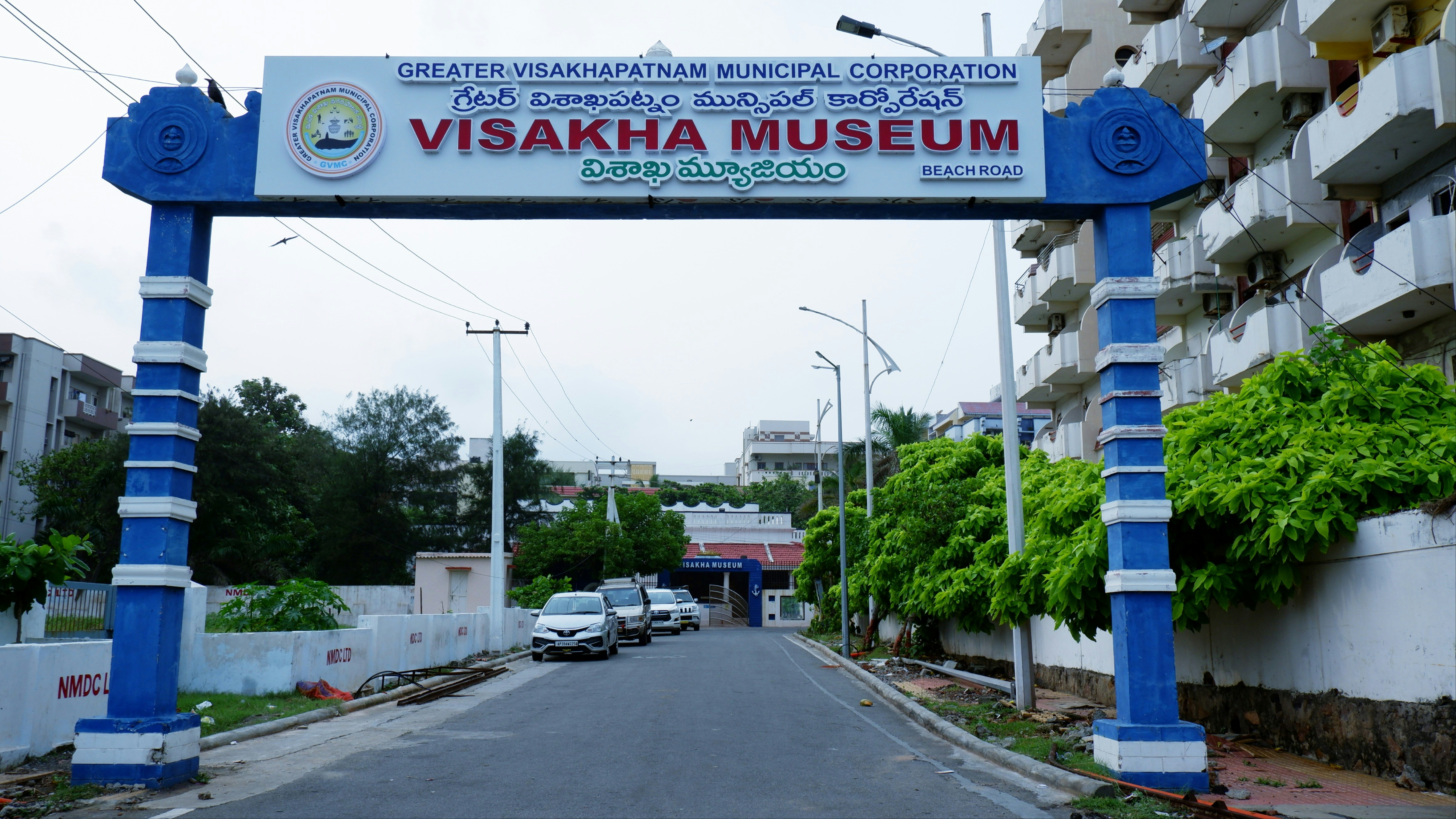 Archway entrance to Visakha Museum, showcasing local municipal branding and vibrant colors. Lush greenery frames the path leading into the museum.