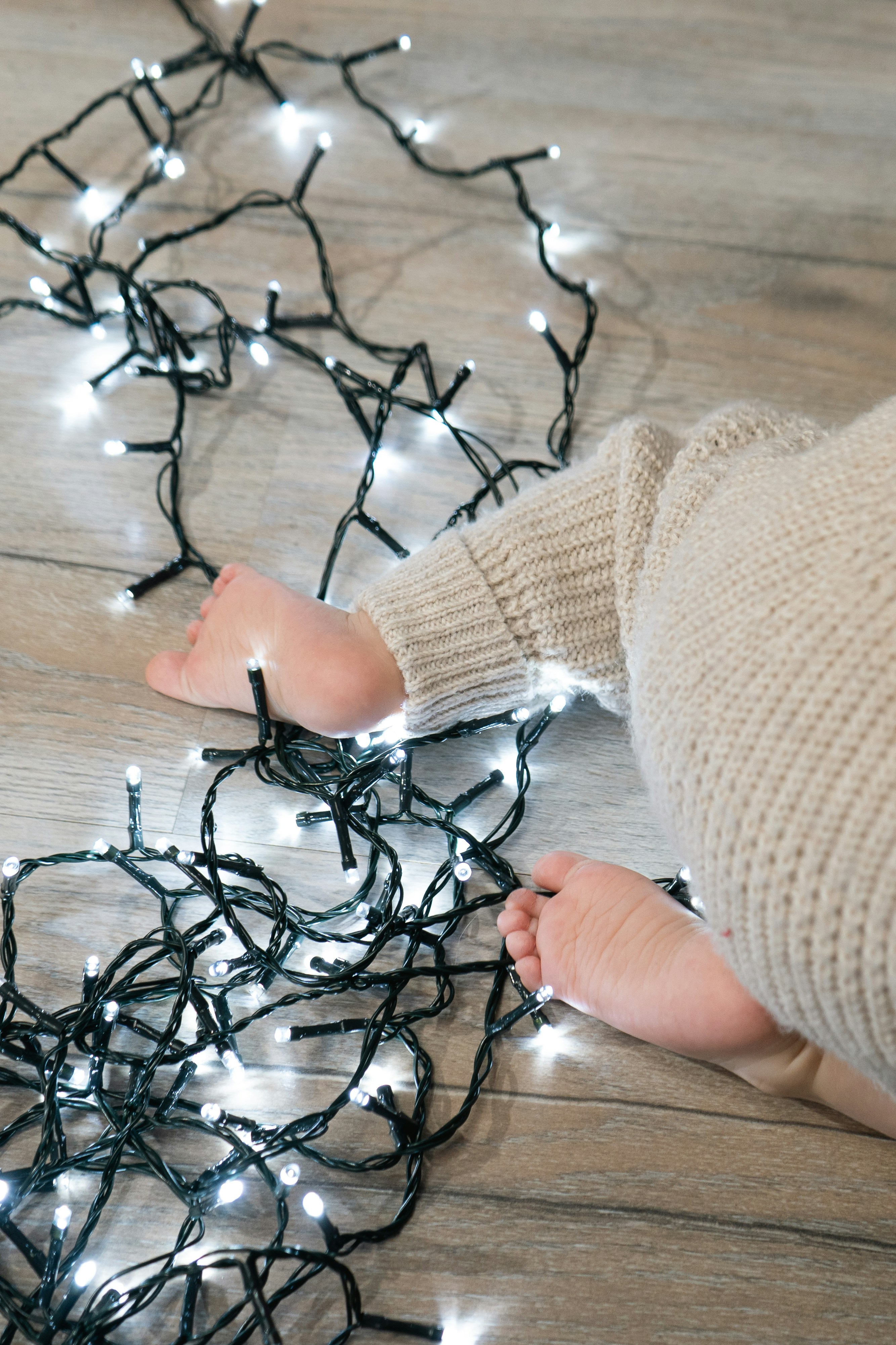 A baby is laying on the floor with a string of lights photo – Free Baby ...