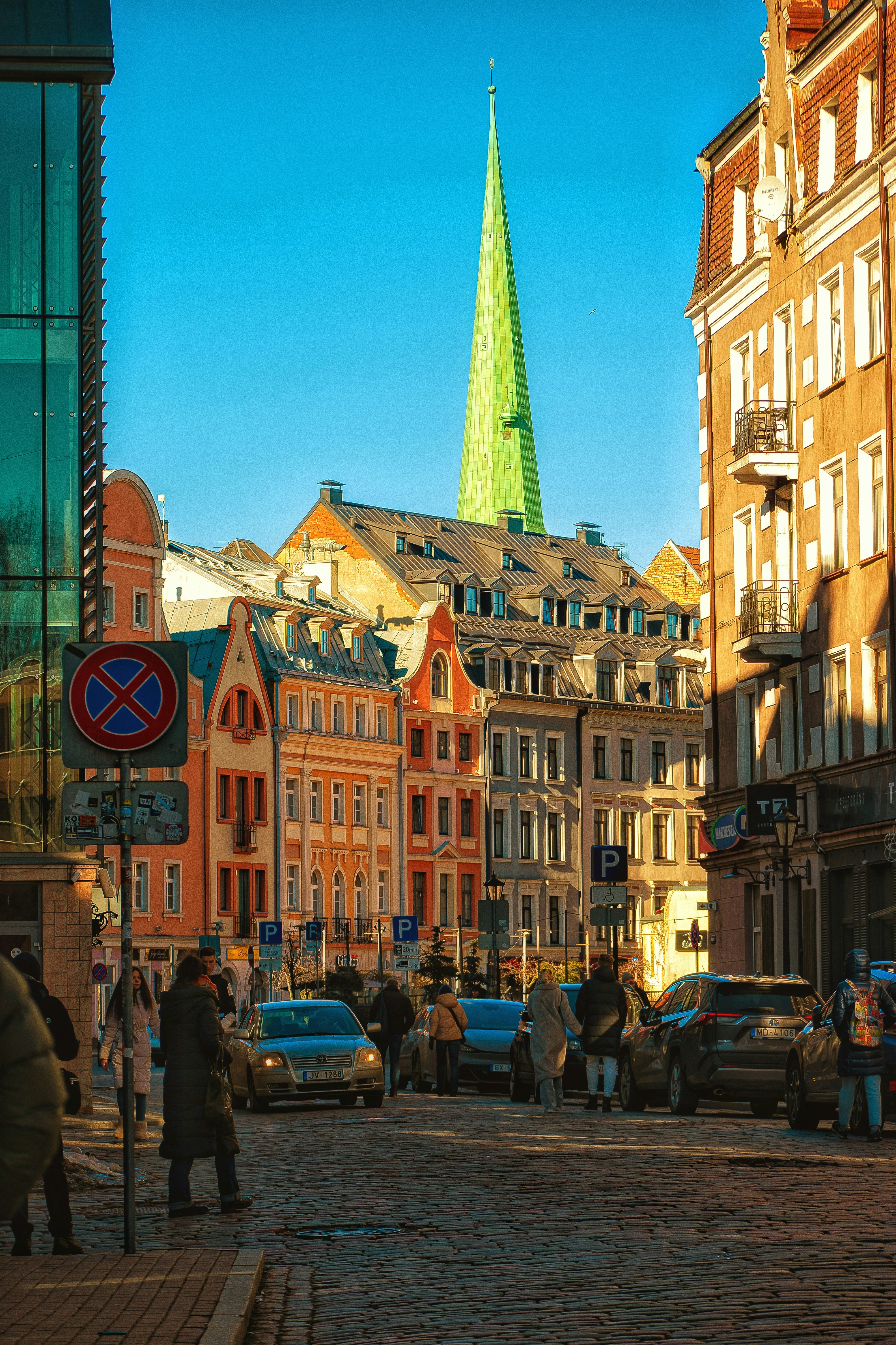A group of people walking down a street next to tall buildings photo ...