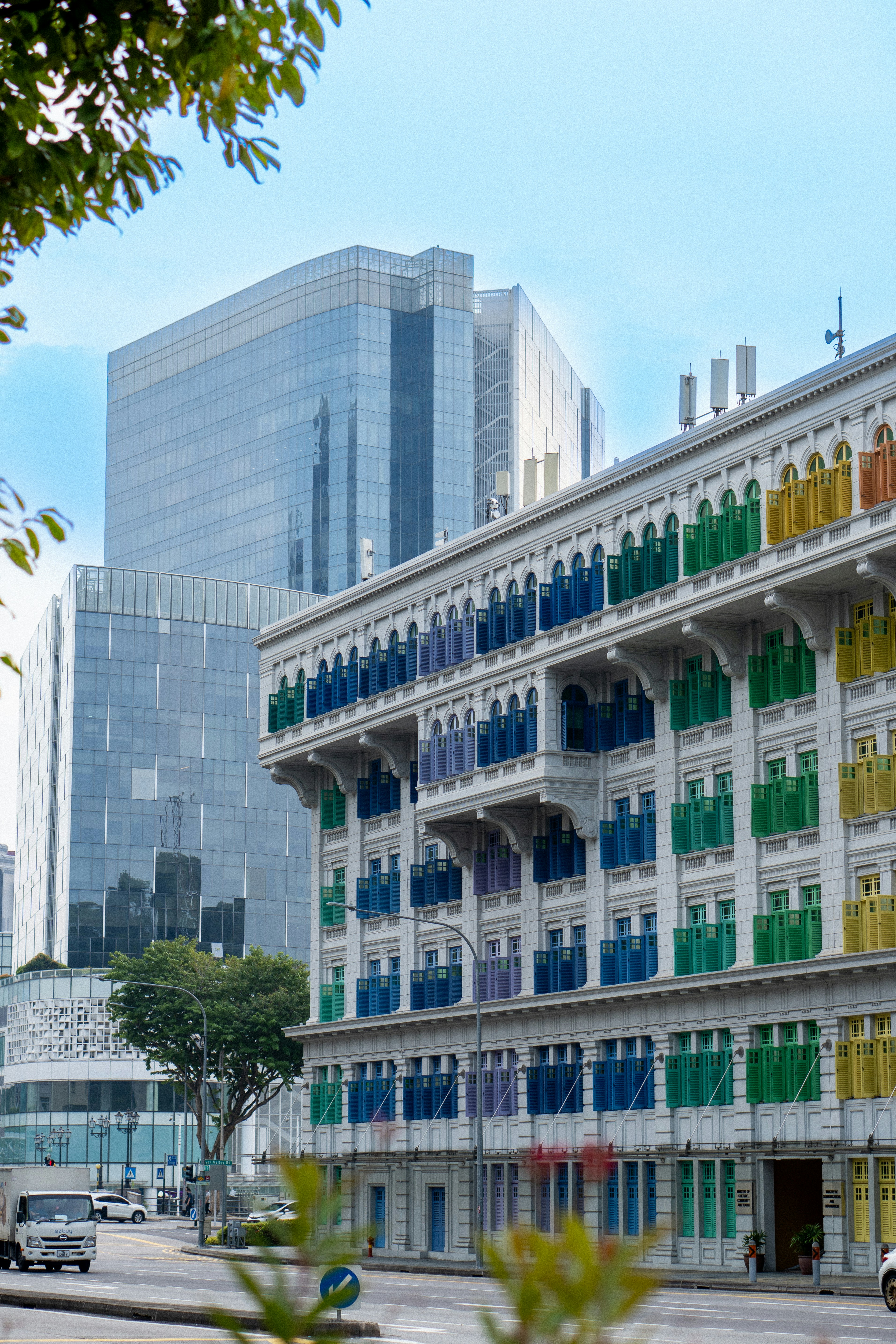 Rainbow Balconies Rise Along a White Facade Beside Sleek Glass Towers