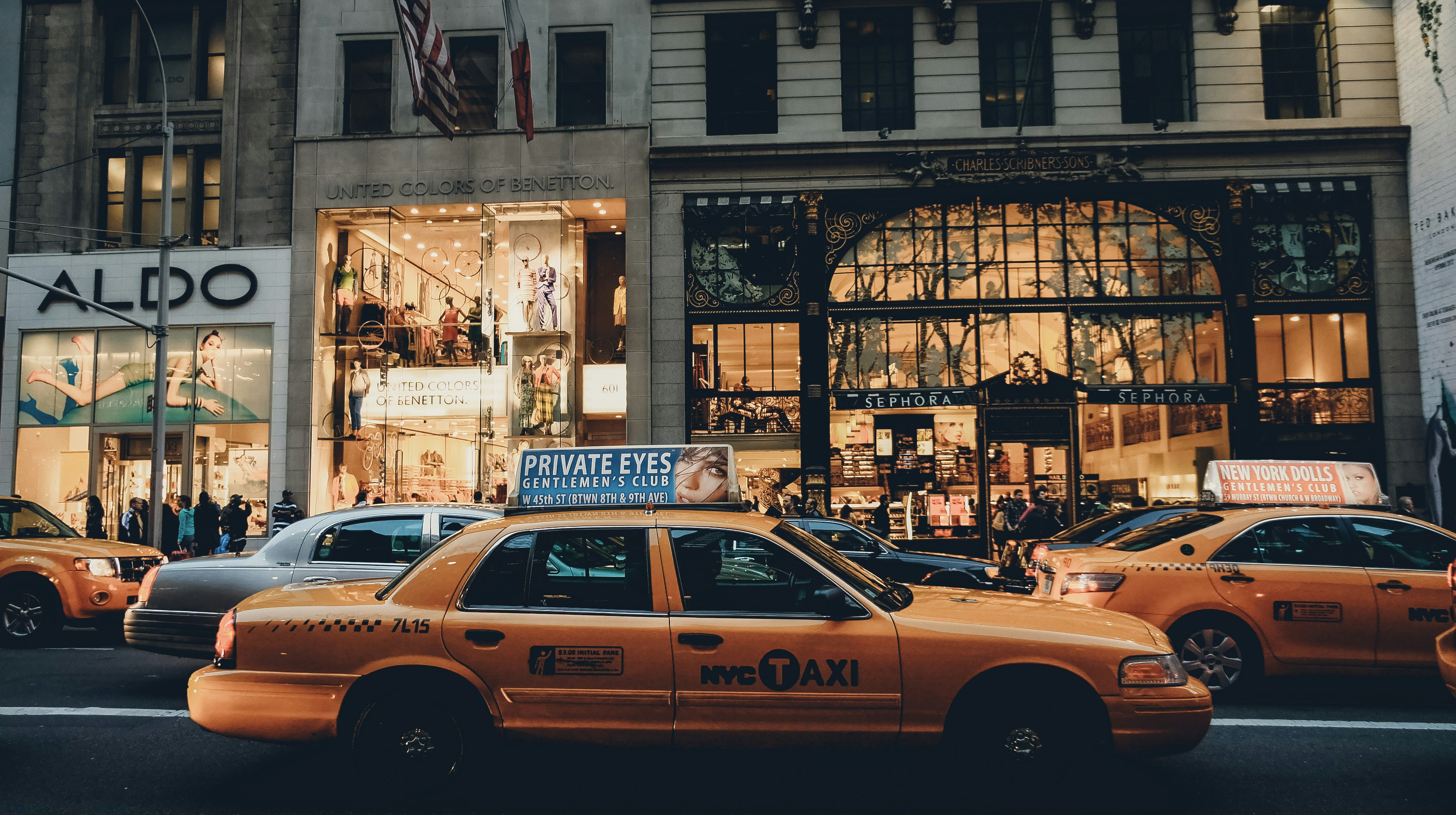 A taxi cab driving down a street next to tall buildings photo – Free ...