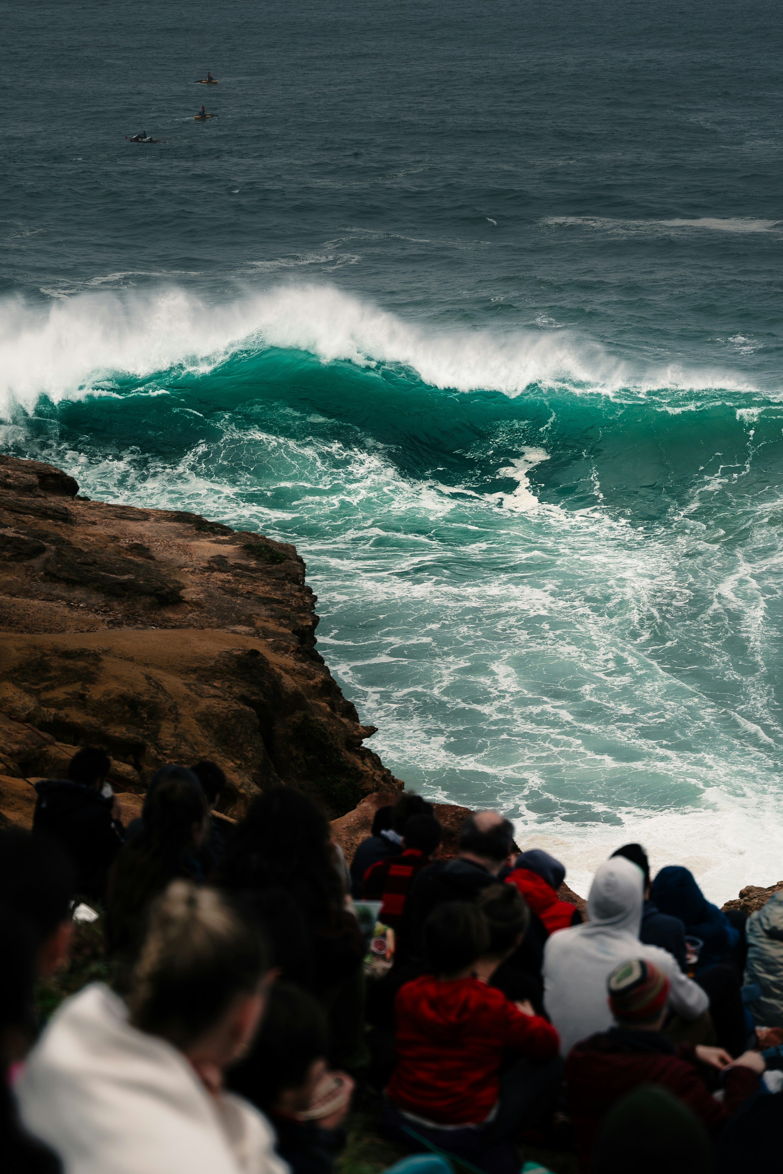 Crowd на the cliff edge watching turquoise breakers