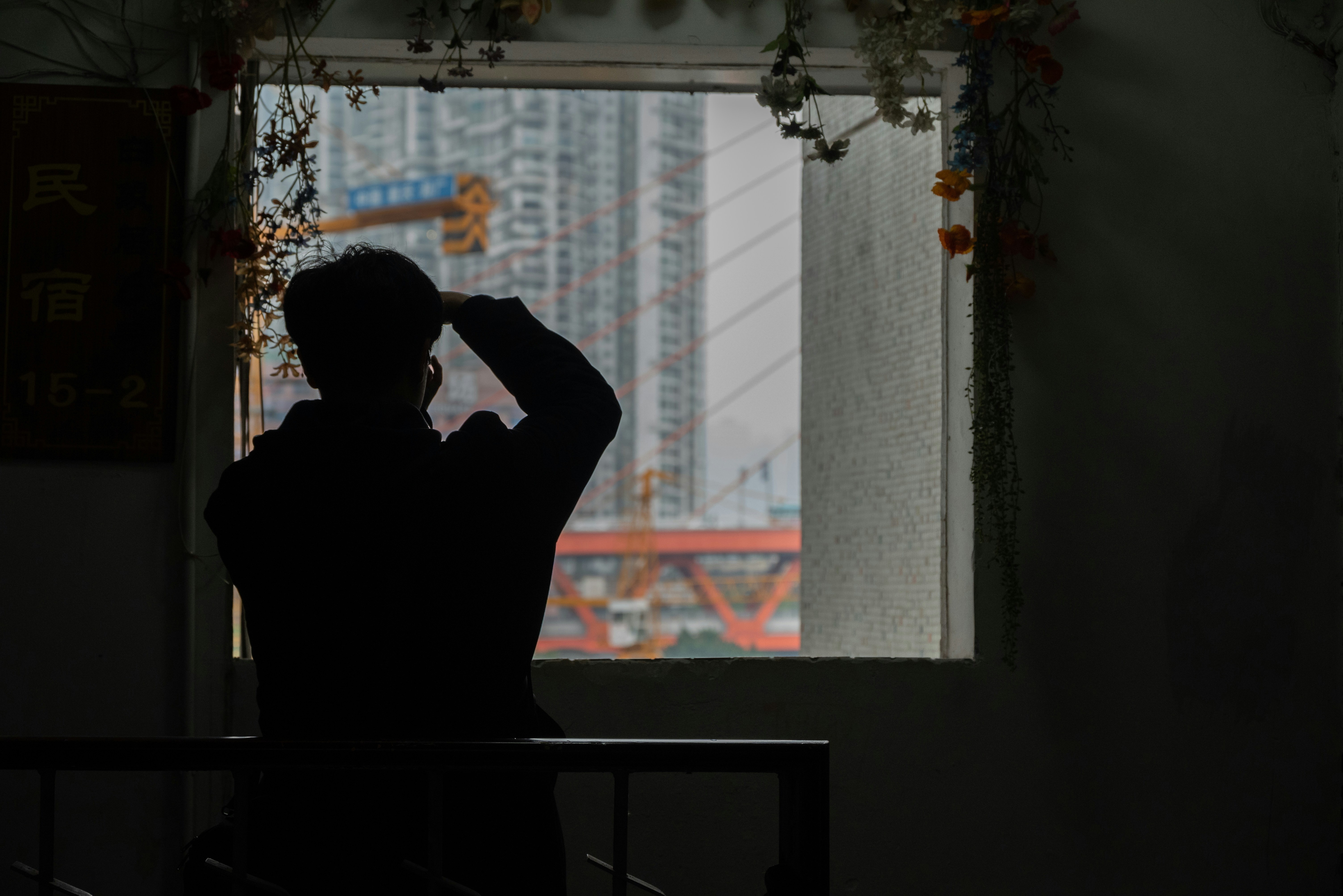A man standing in front of a window with a cell phone to his ear photo ...