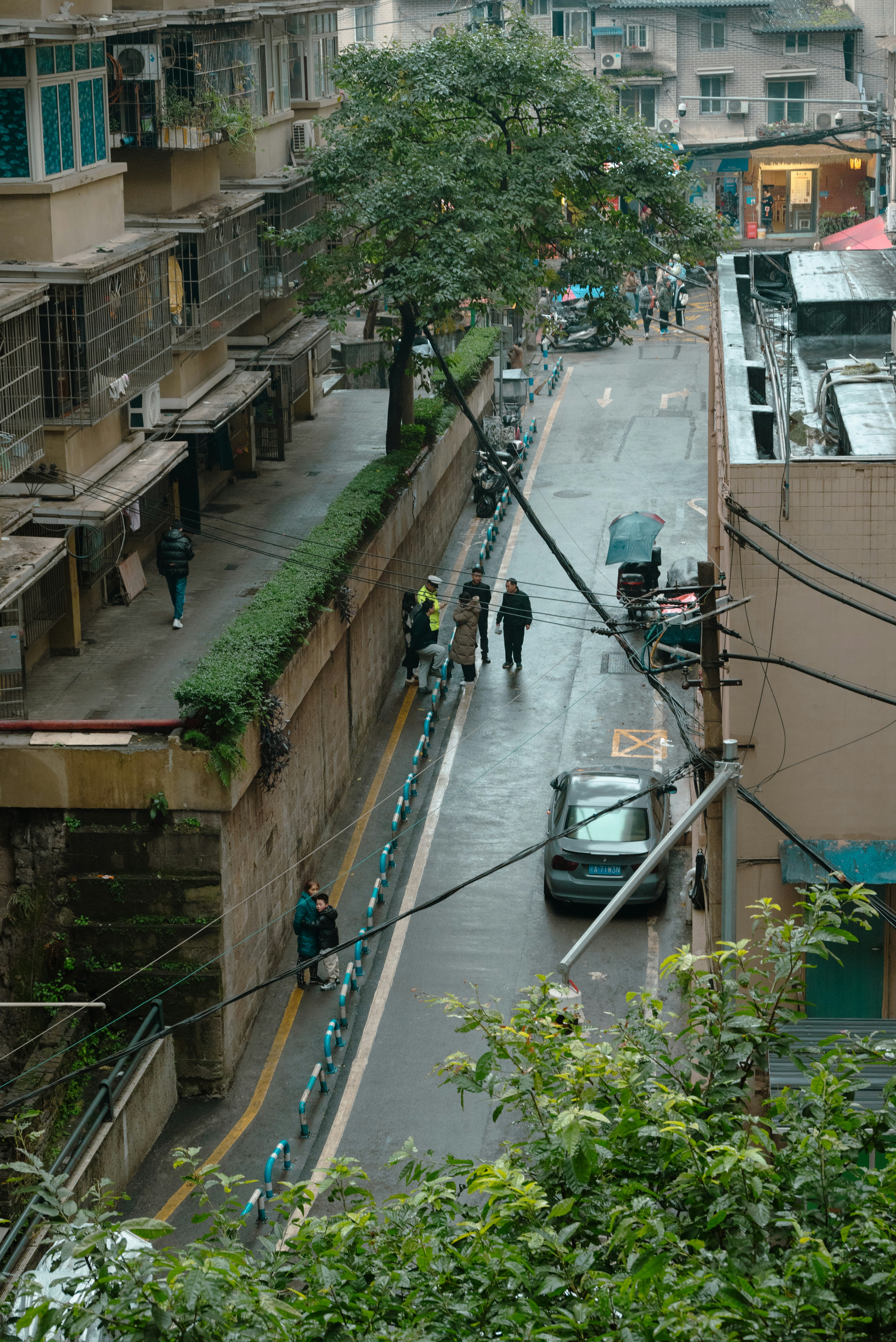 A couple of people walking down a rain soaked street photo – Free Chong ...