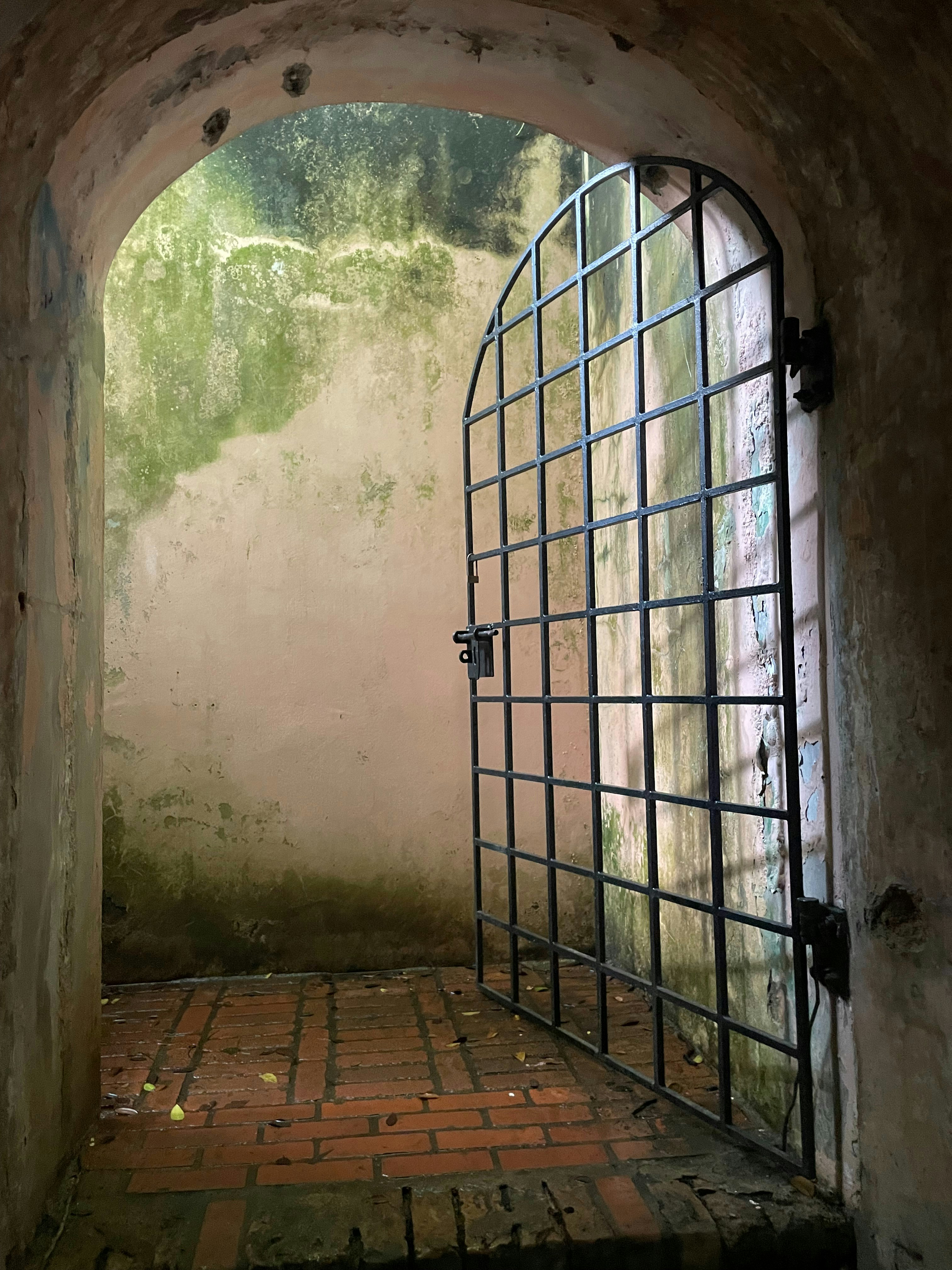 A jail cell with bars and a brick floor photo – Free Brown Image on ...