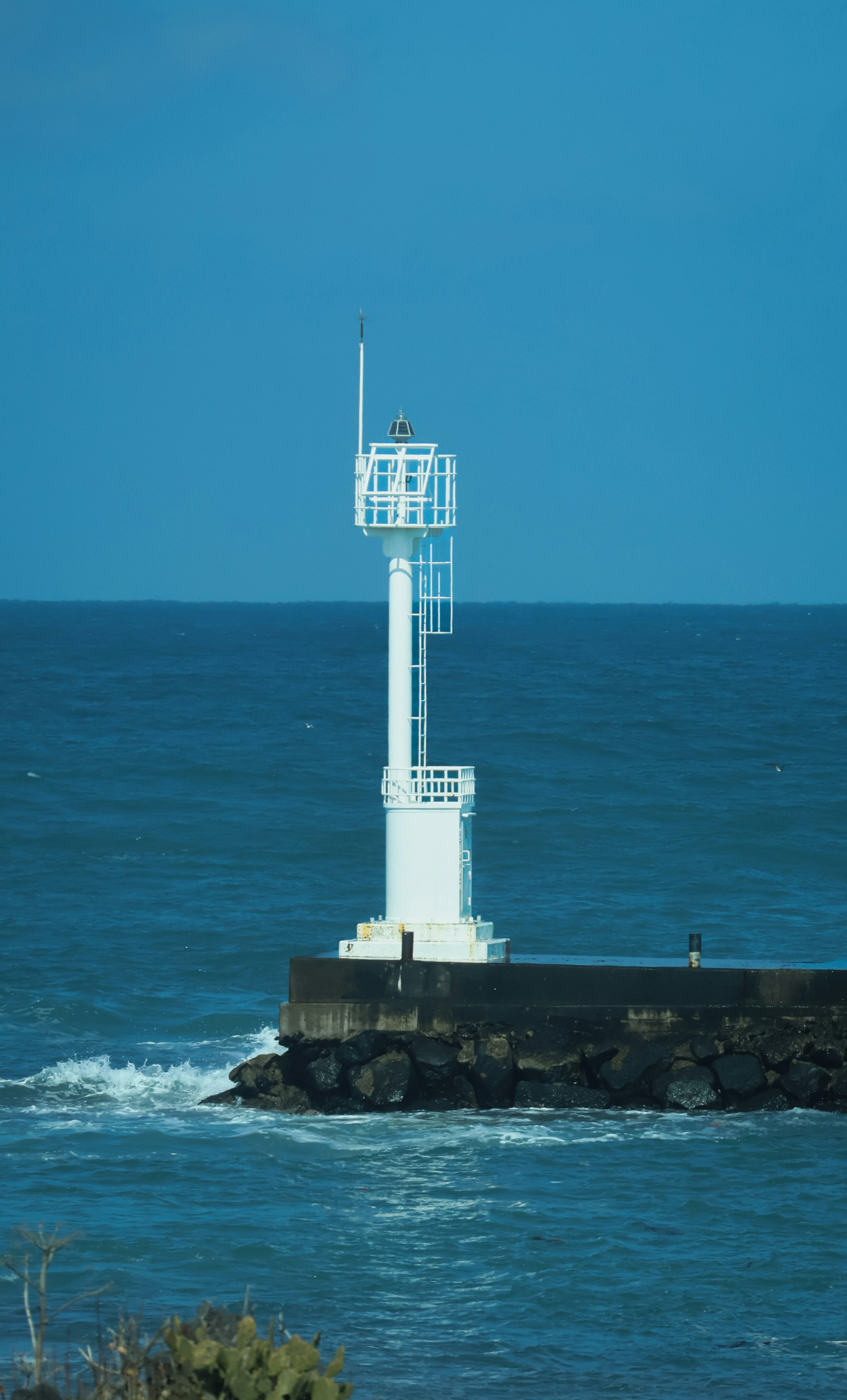 A white lighthouse sitting on top of a pier next to the ocean photo ...