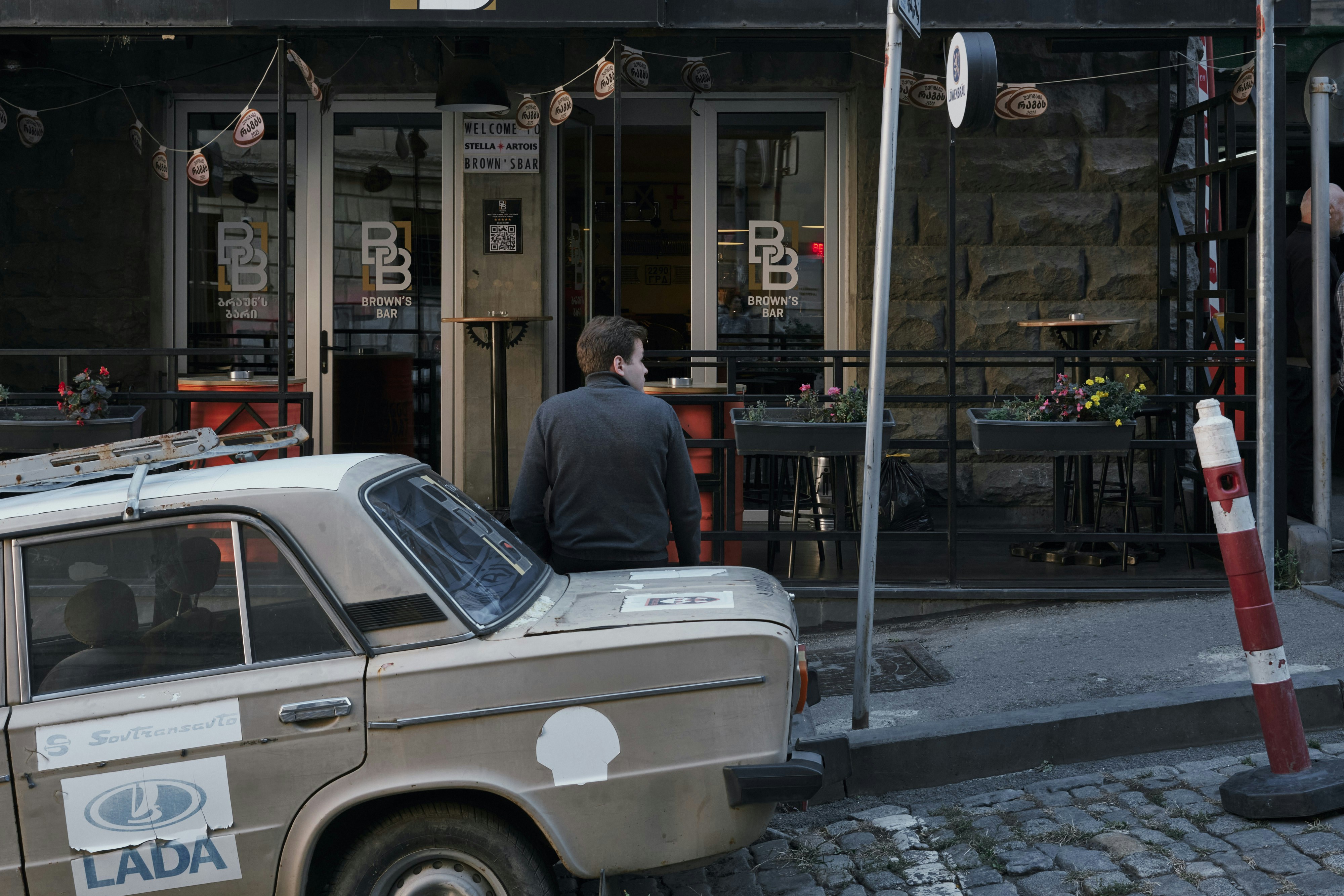 Retro Pause by a Weathered Lada on a Cobblestone Street