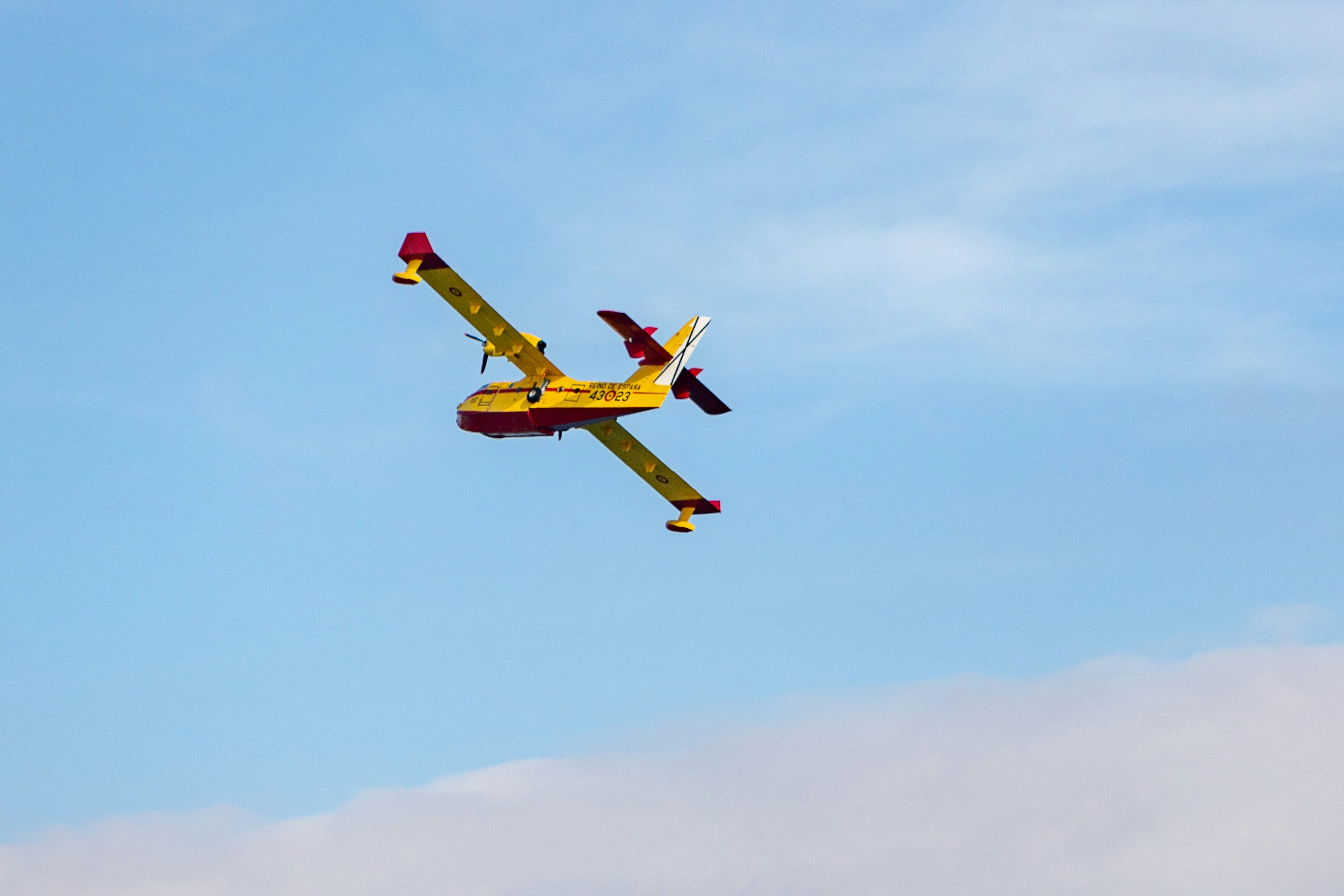 A yellow and red plane flying in the sky photo – Free Flying Image on ...