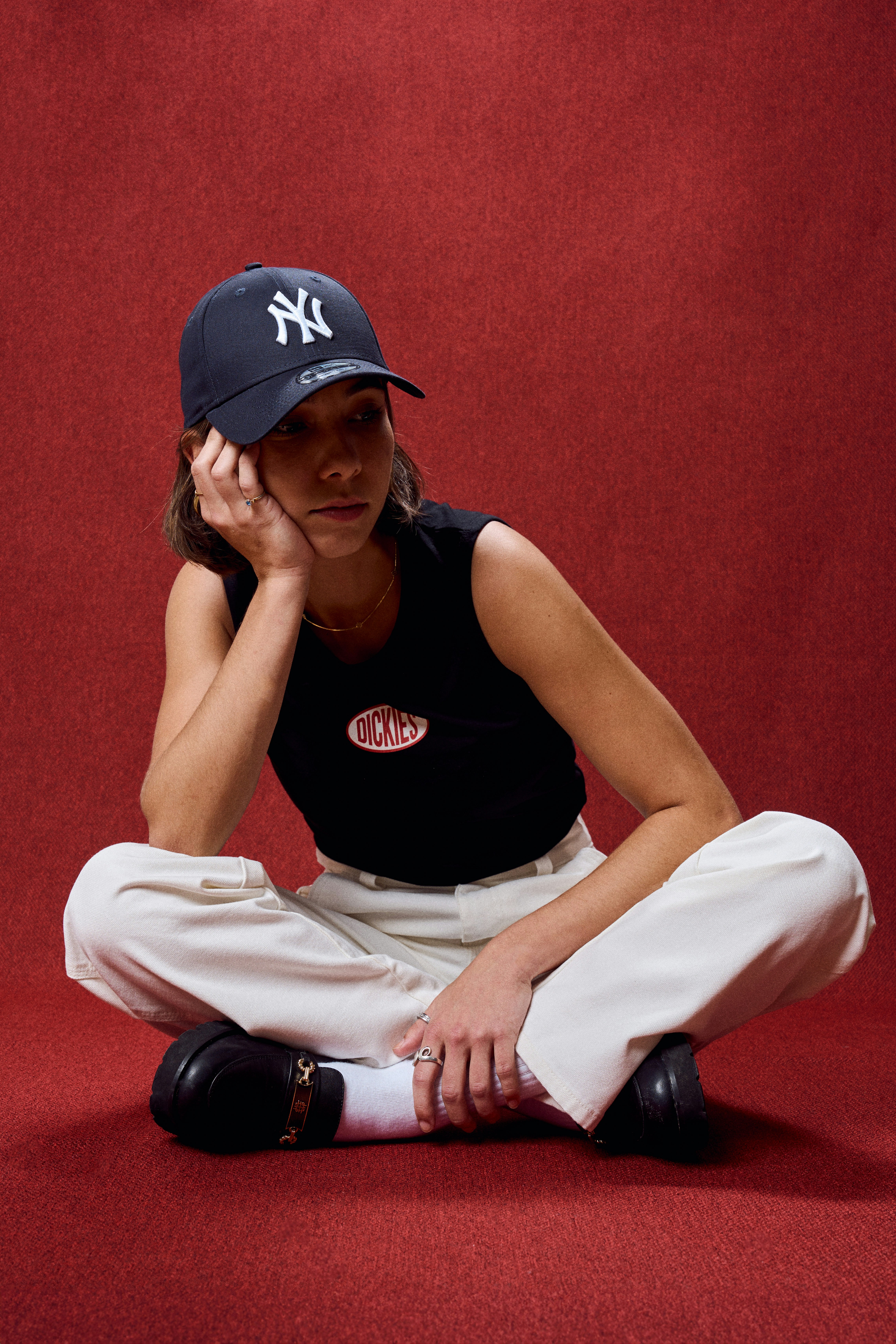 A woman sitting on the ground wearing a new york yankees hat photo ...