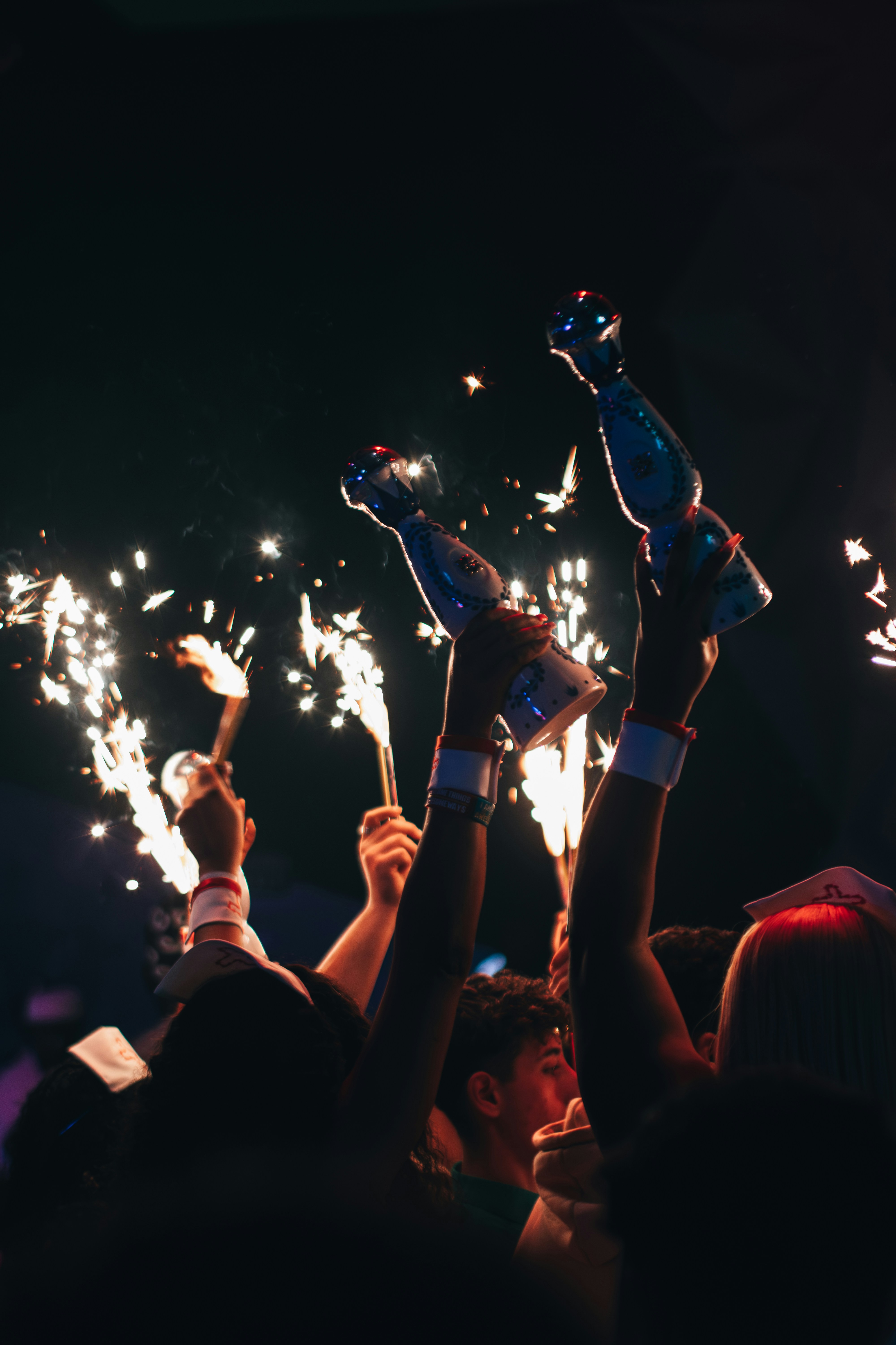 A group of people holding sparklers in the air photo – Free Bottle ...