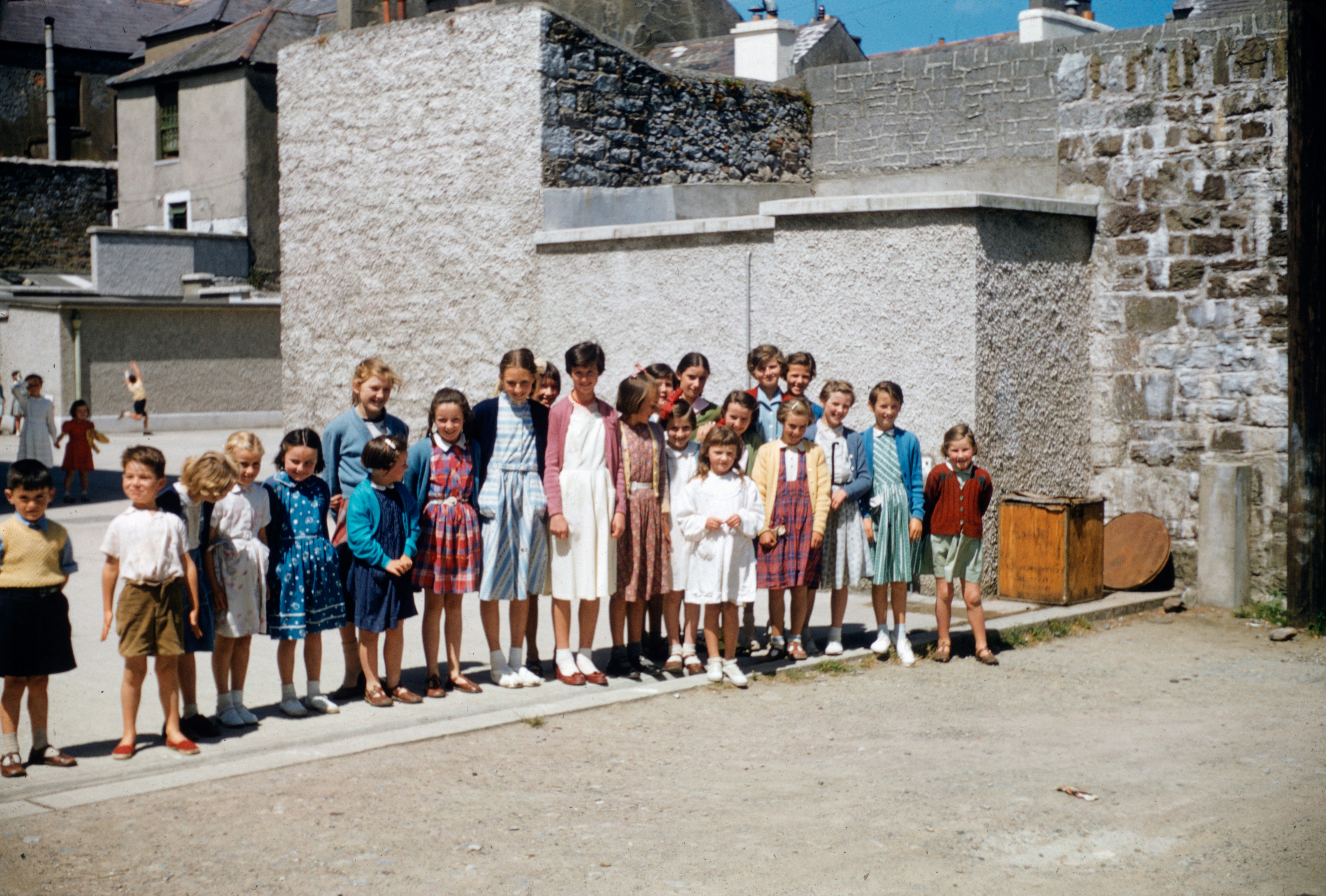 Line of children on a sunlit courtyard in a village