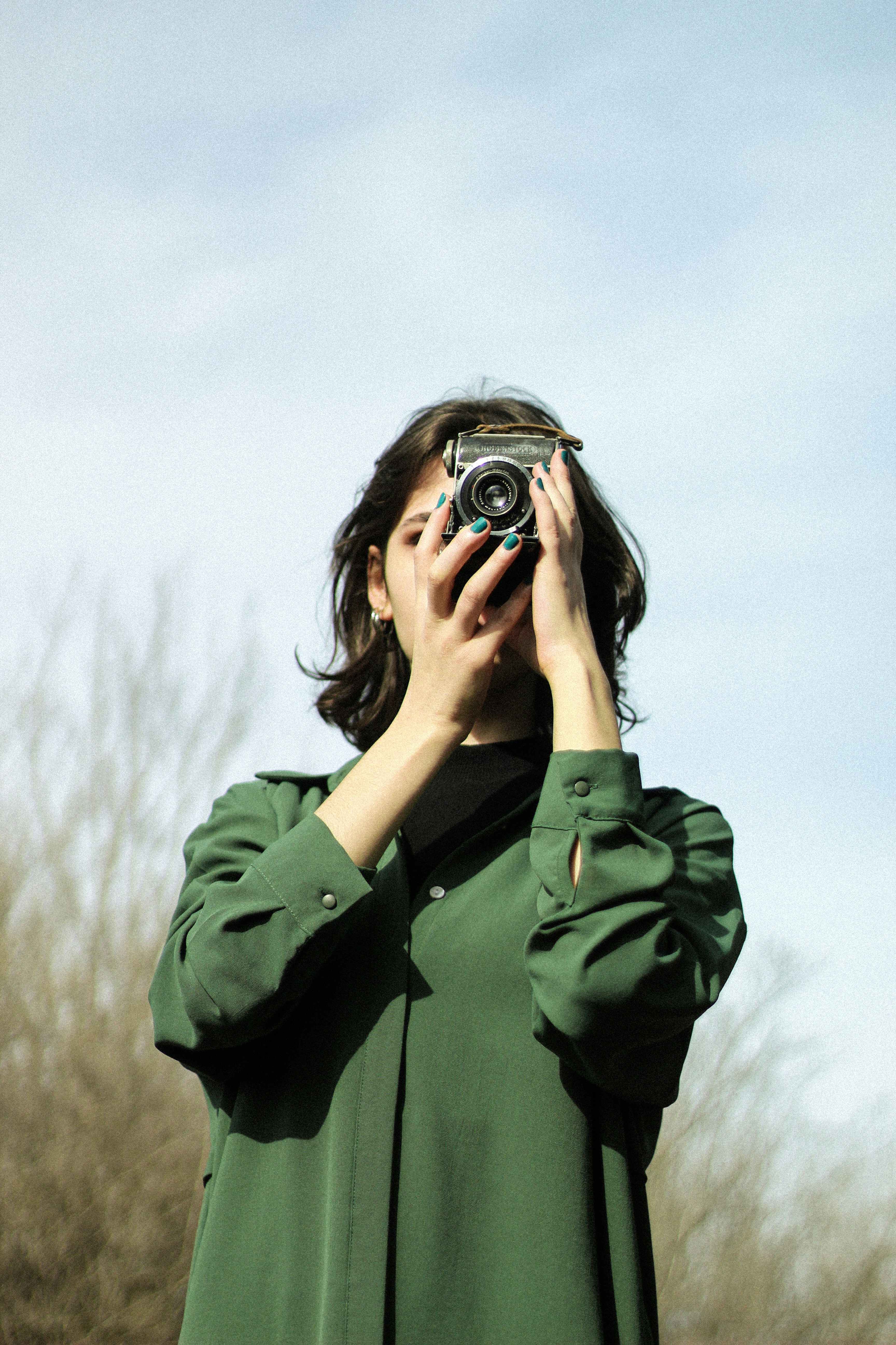 Behind the Lens in Light: A Green-Clad Photographer under an Open Sky