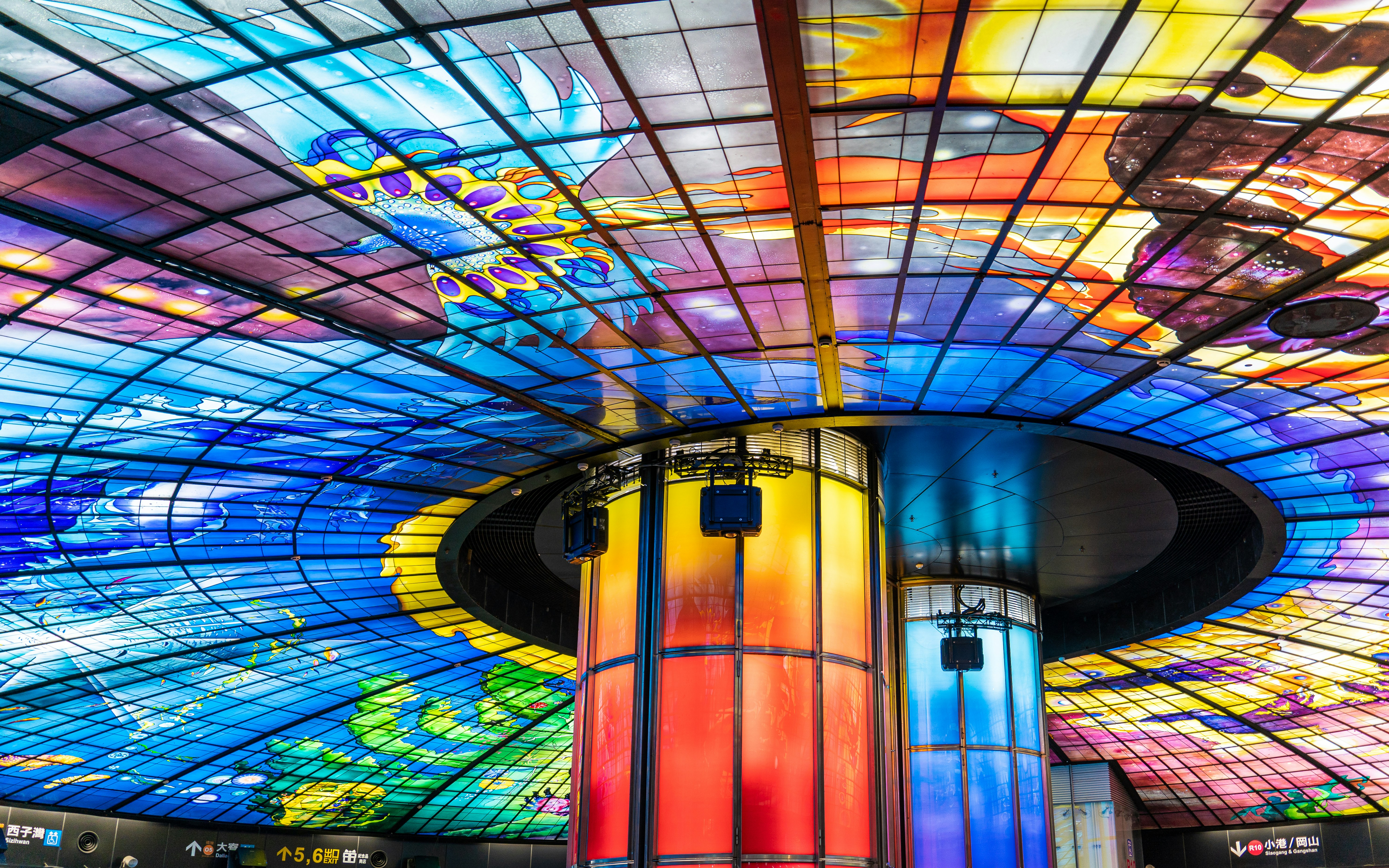 Vibrant stained glass dome with intricate designs and vivid colors in a public space.