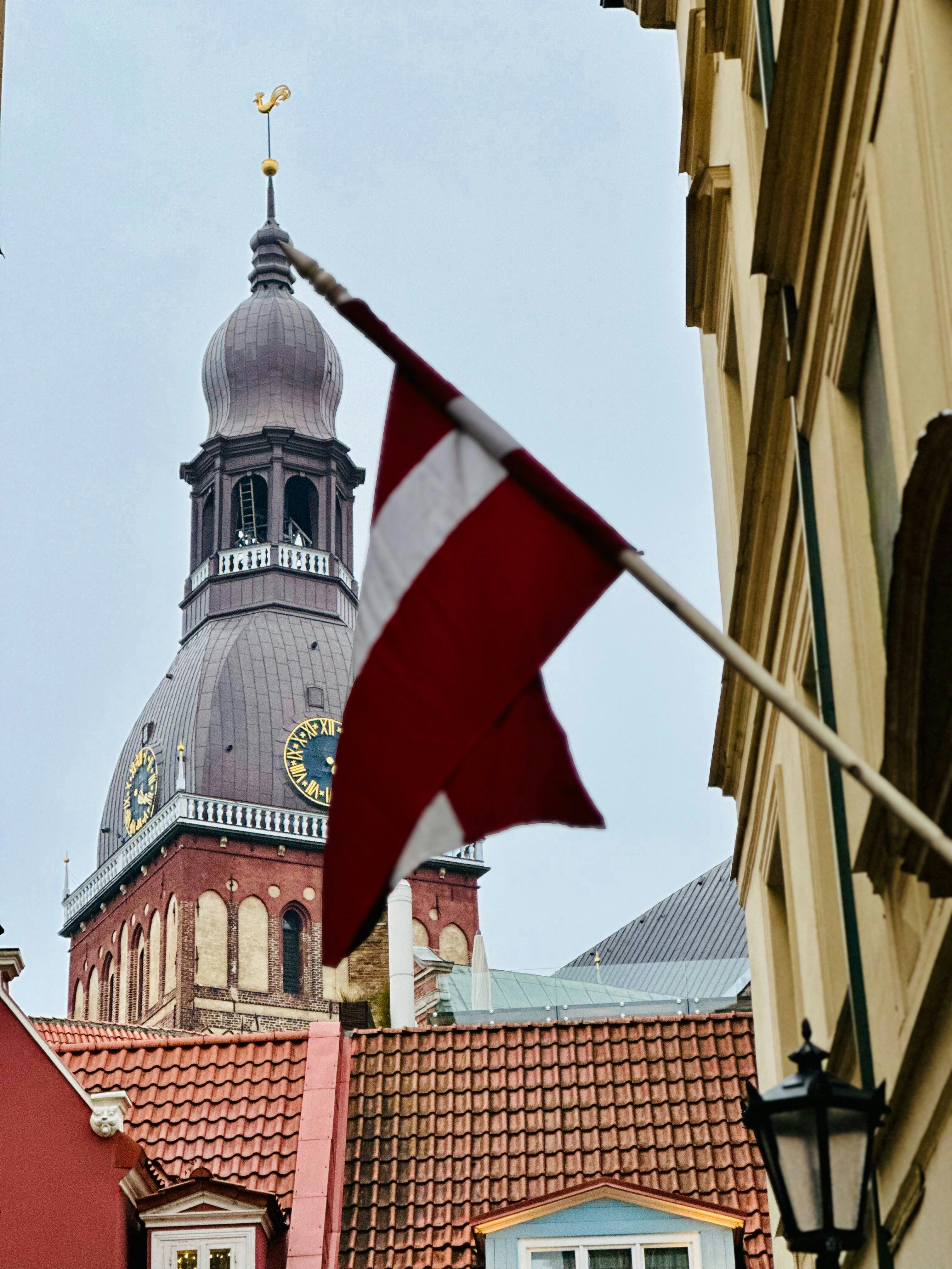 Clock Tower Rising Over Red Roofs, Framed by a Fluttering Flag
