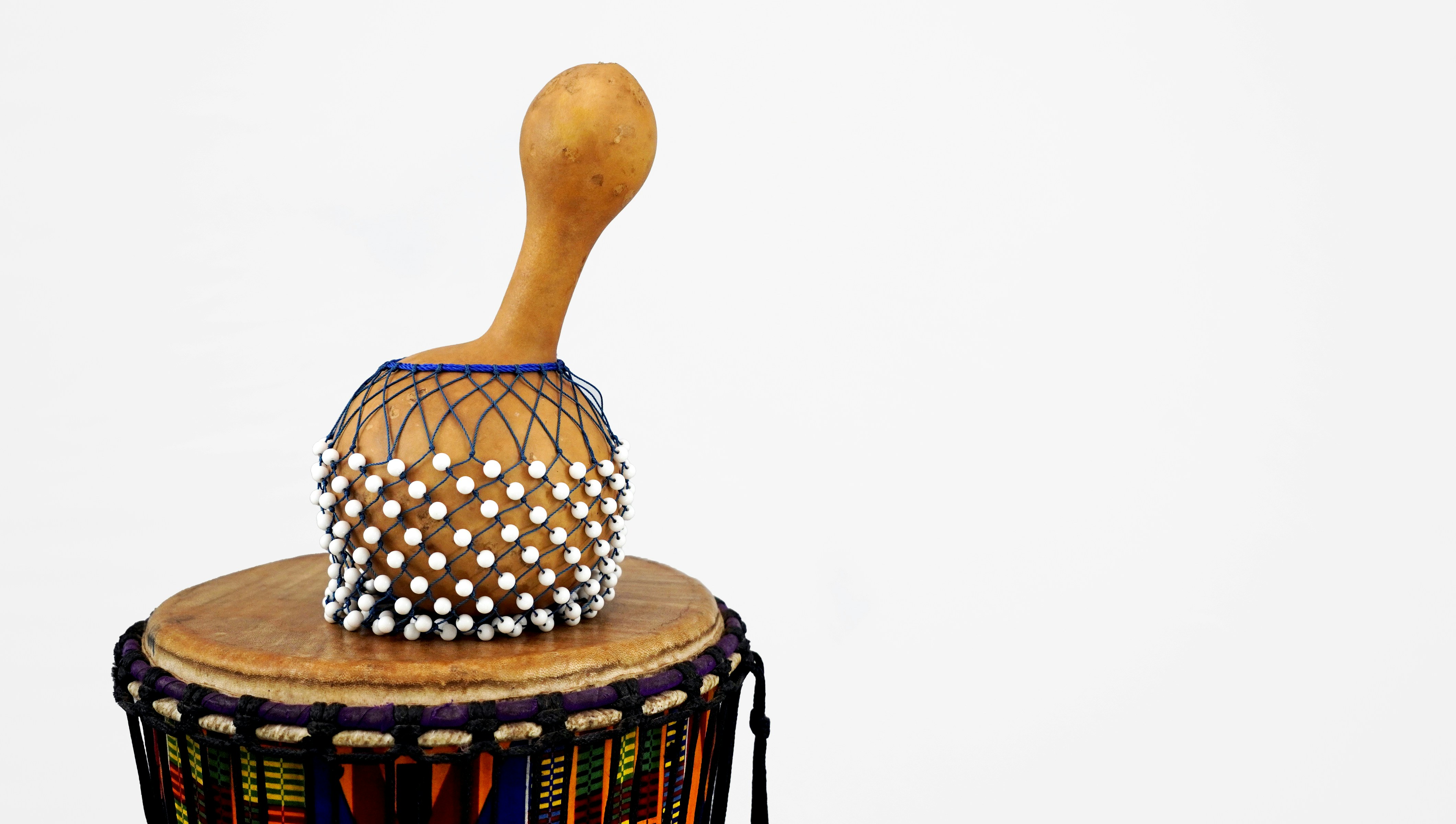 Beaded Gourd on a Djembe: Quiet Rhythm in White Studio