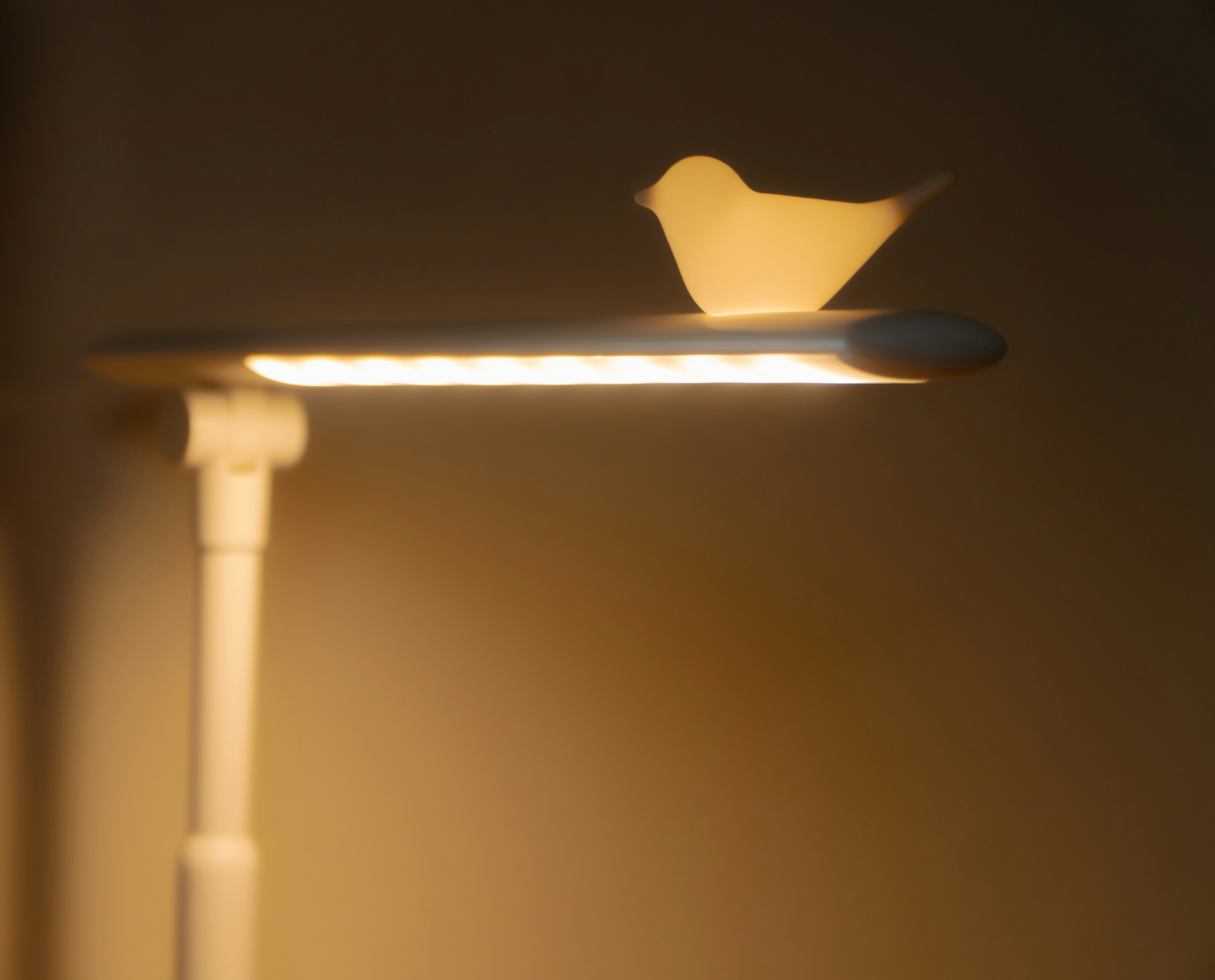 Amber Hour: A Silhouette Bird Perches Above a Dim Desk Lamp