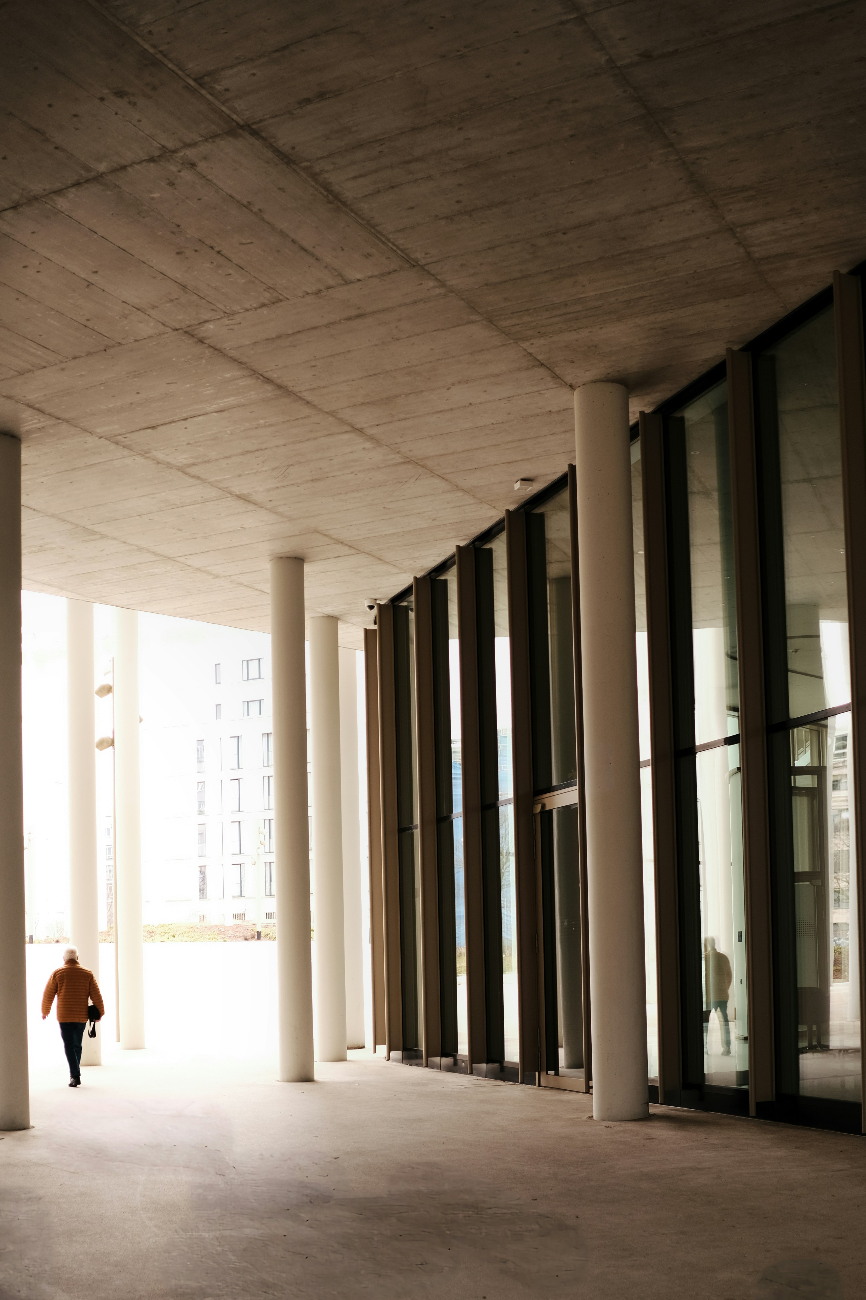 A person walking down a hallway between two buildings photo – Free Men ...