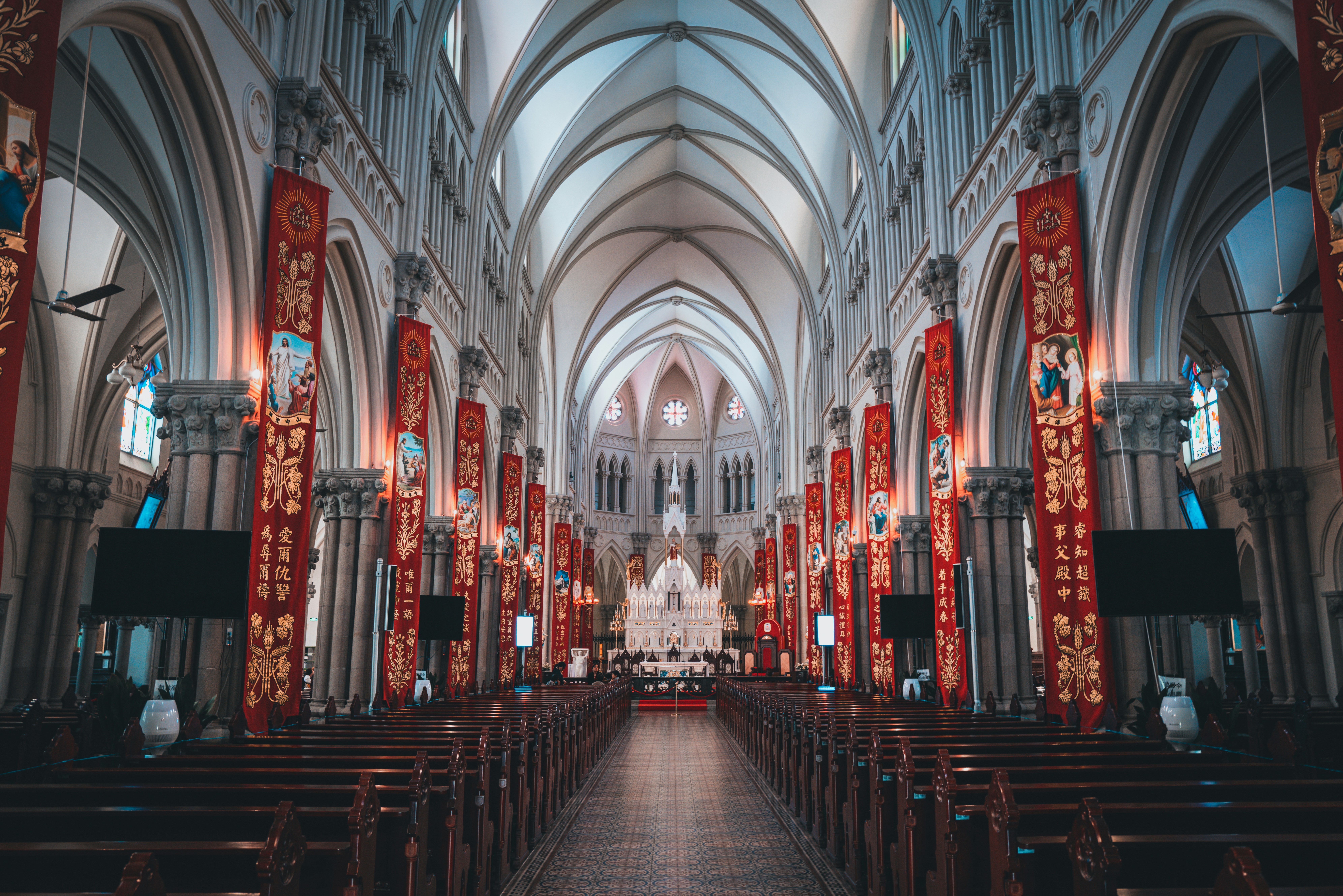 Cruciform Echoes: Red banners frame the nave toward the illuminated altar