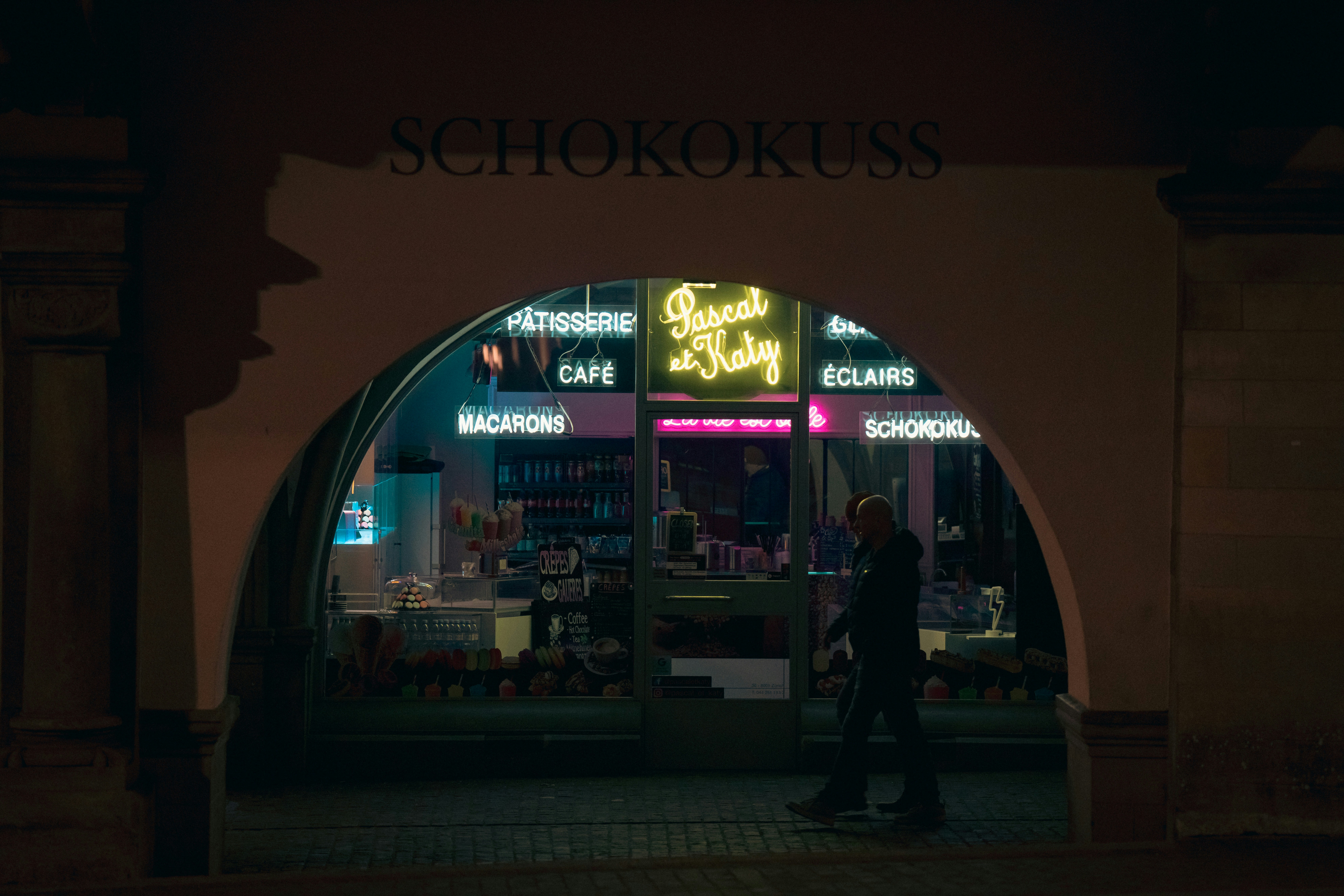 A man walking past a store front at night photo – Free Street ...