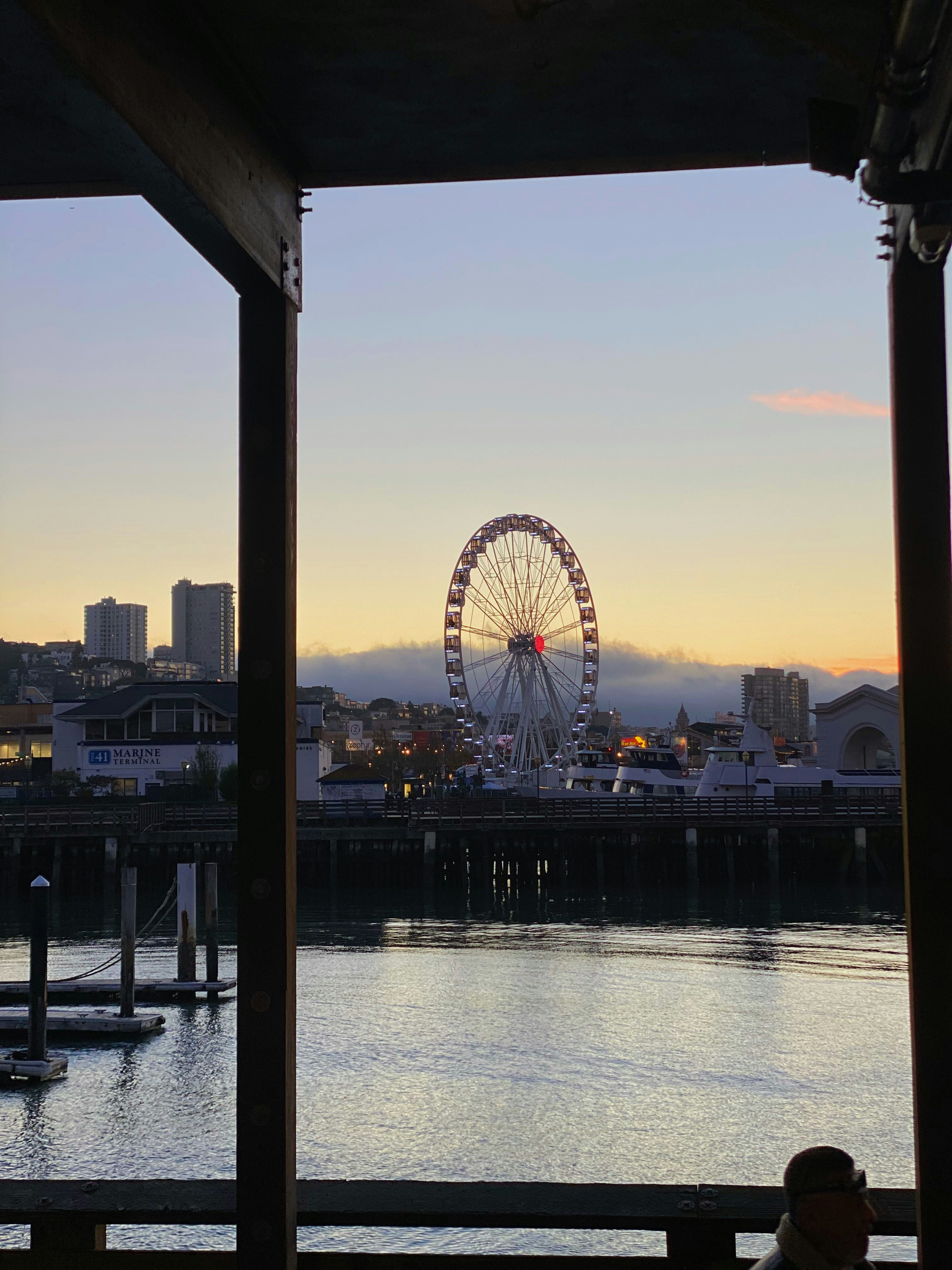 Horizon Loop: Sunset Over a Waterfront Ferris Wheel Framed by Pier Beams