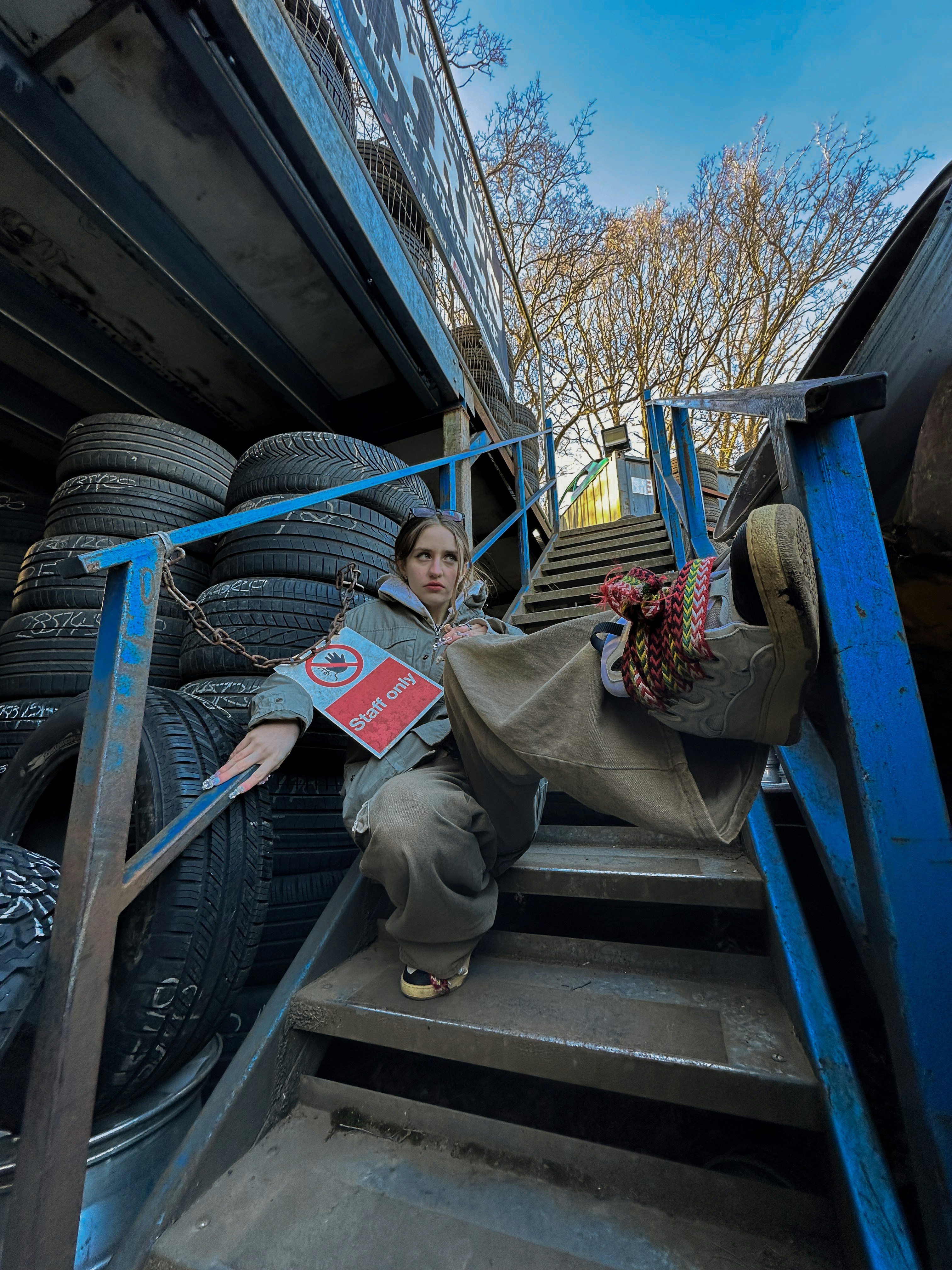 Staircase Portrait in a Tire Yard: Quiet Resolve Among Rubber