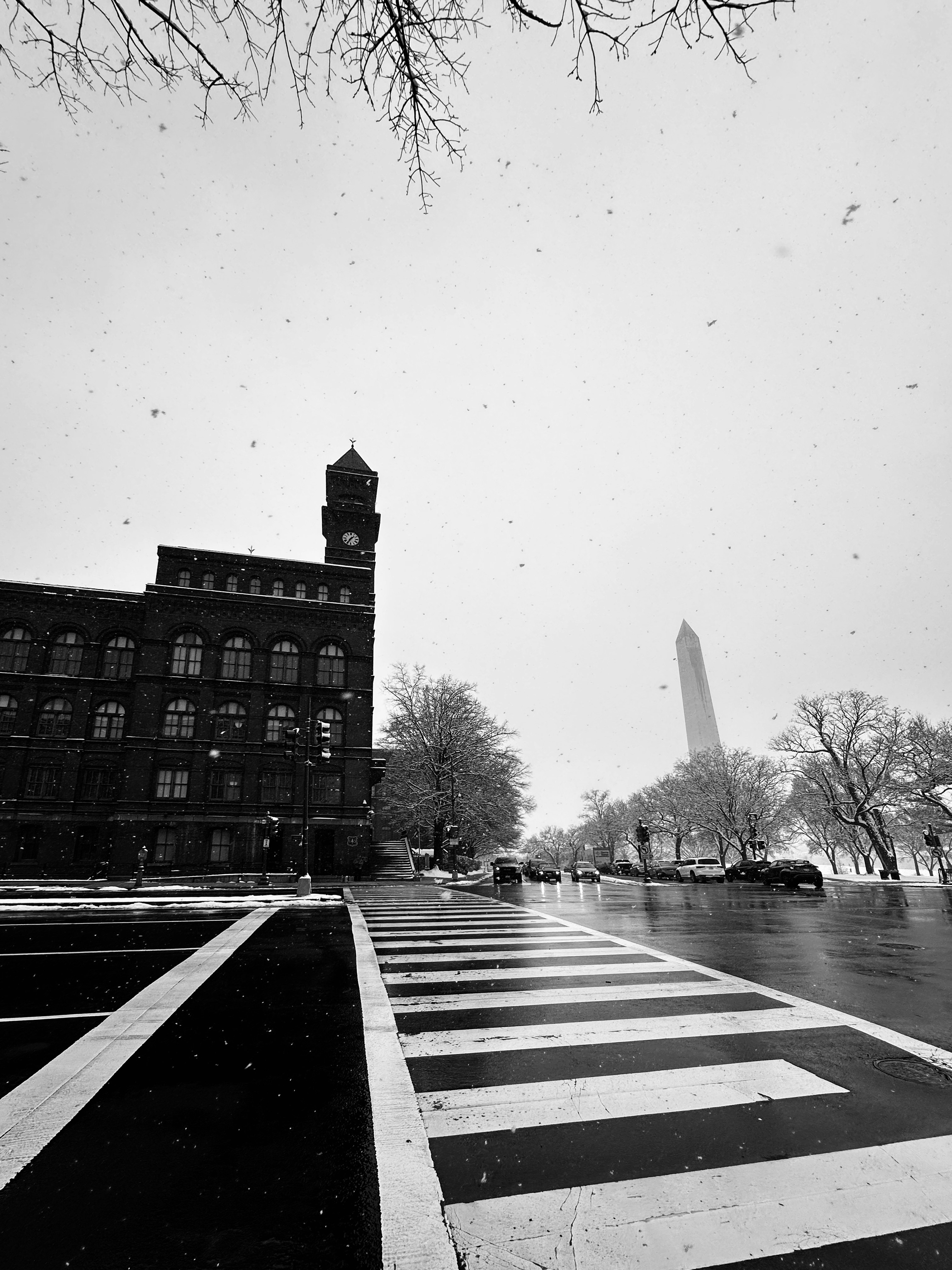 Snowfall at the Crosswalk: A Clock-Tower Brick Facade Framing the DC Obelisk
