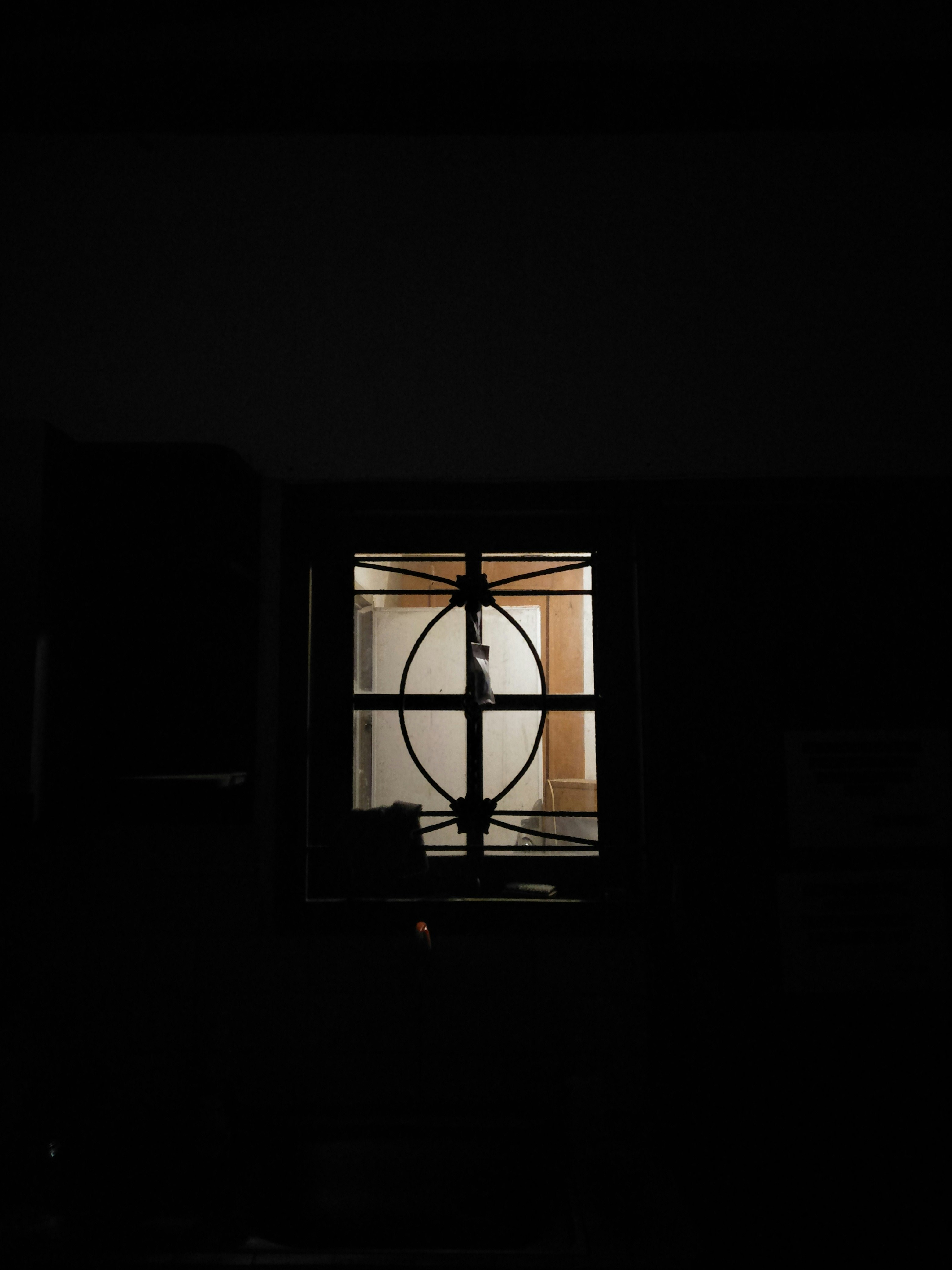 Photograph of a dark interior featuring a bright circular window with a crossbar grid.