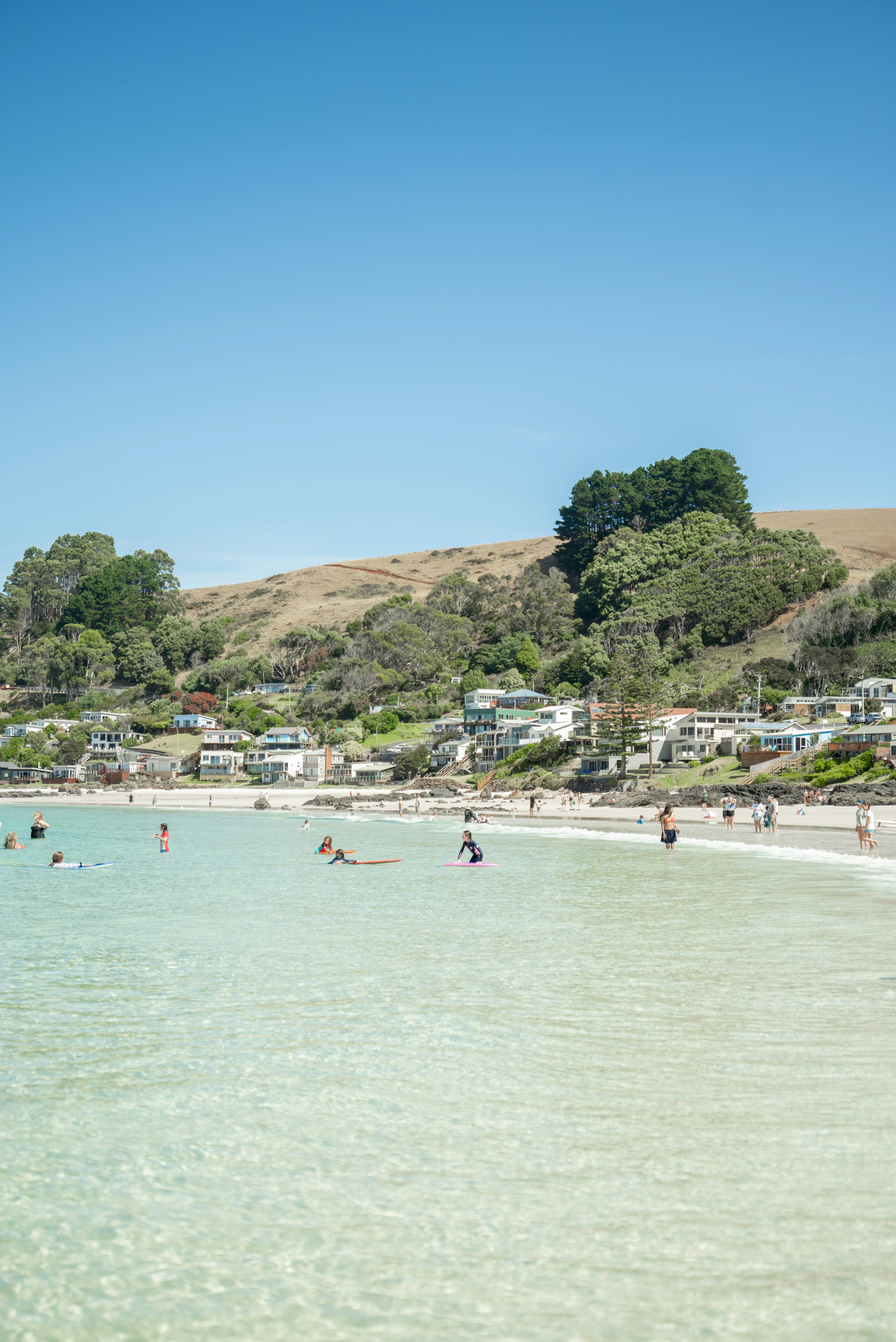 Mint-Turquoise Bay: A Sunlit Shoreline Framed by Hilltop Homes