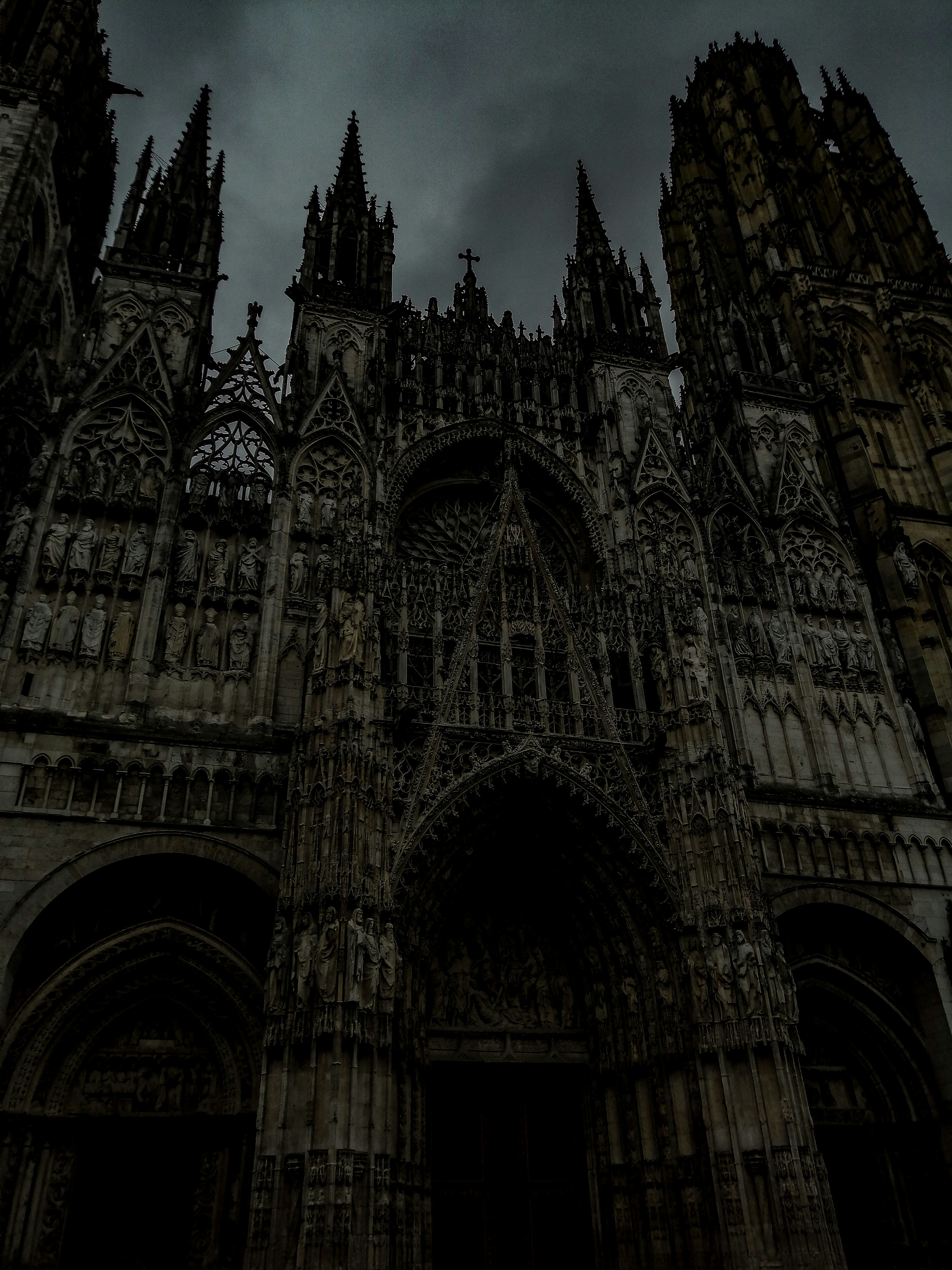 Intricate Gothic cathedral facade silhouetted against a dark, cloudy sky.
