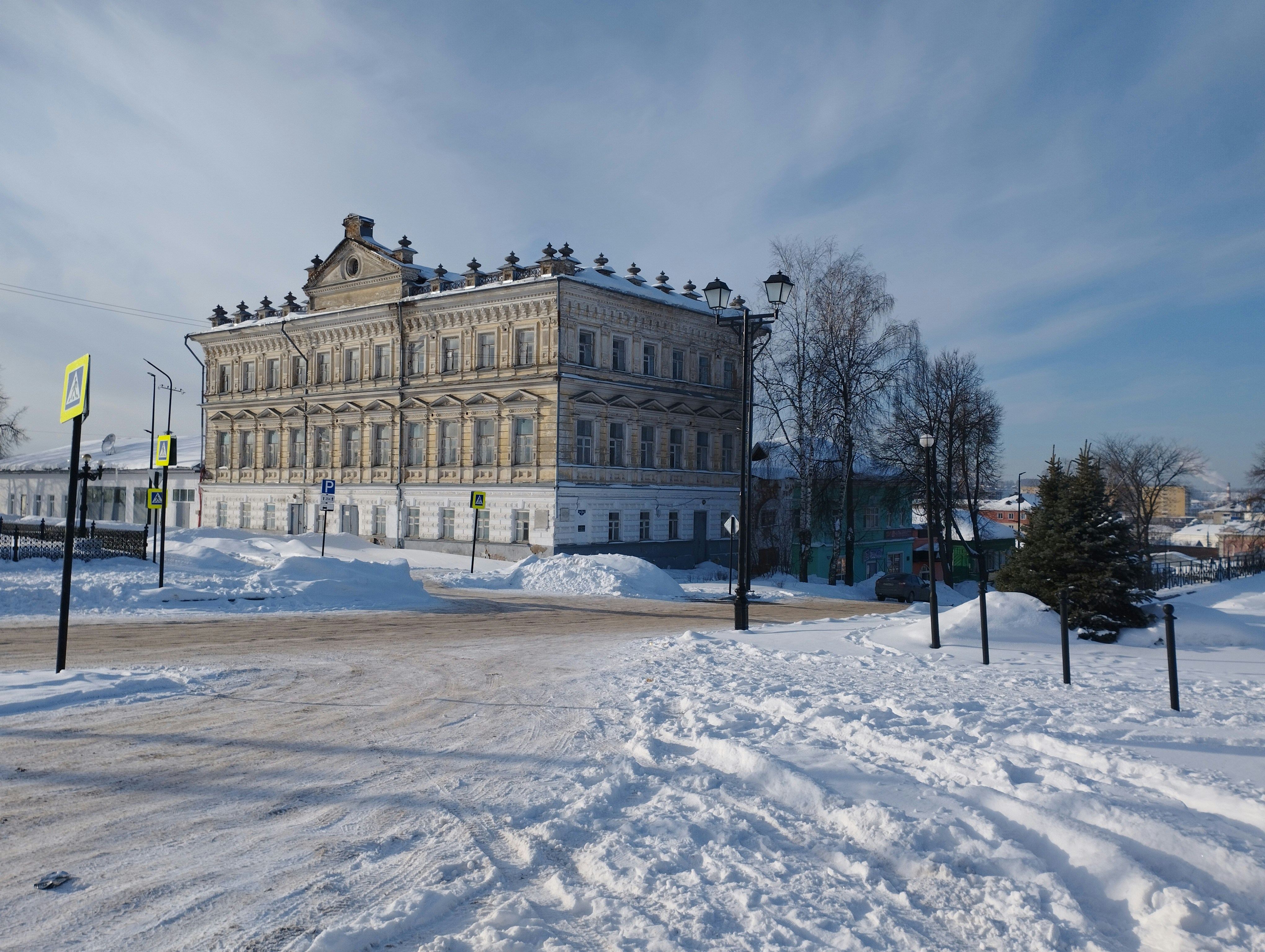Grand building standing beside a snow-covered road under a clear blue sky.