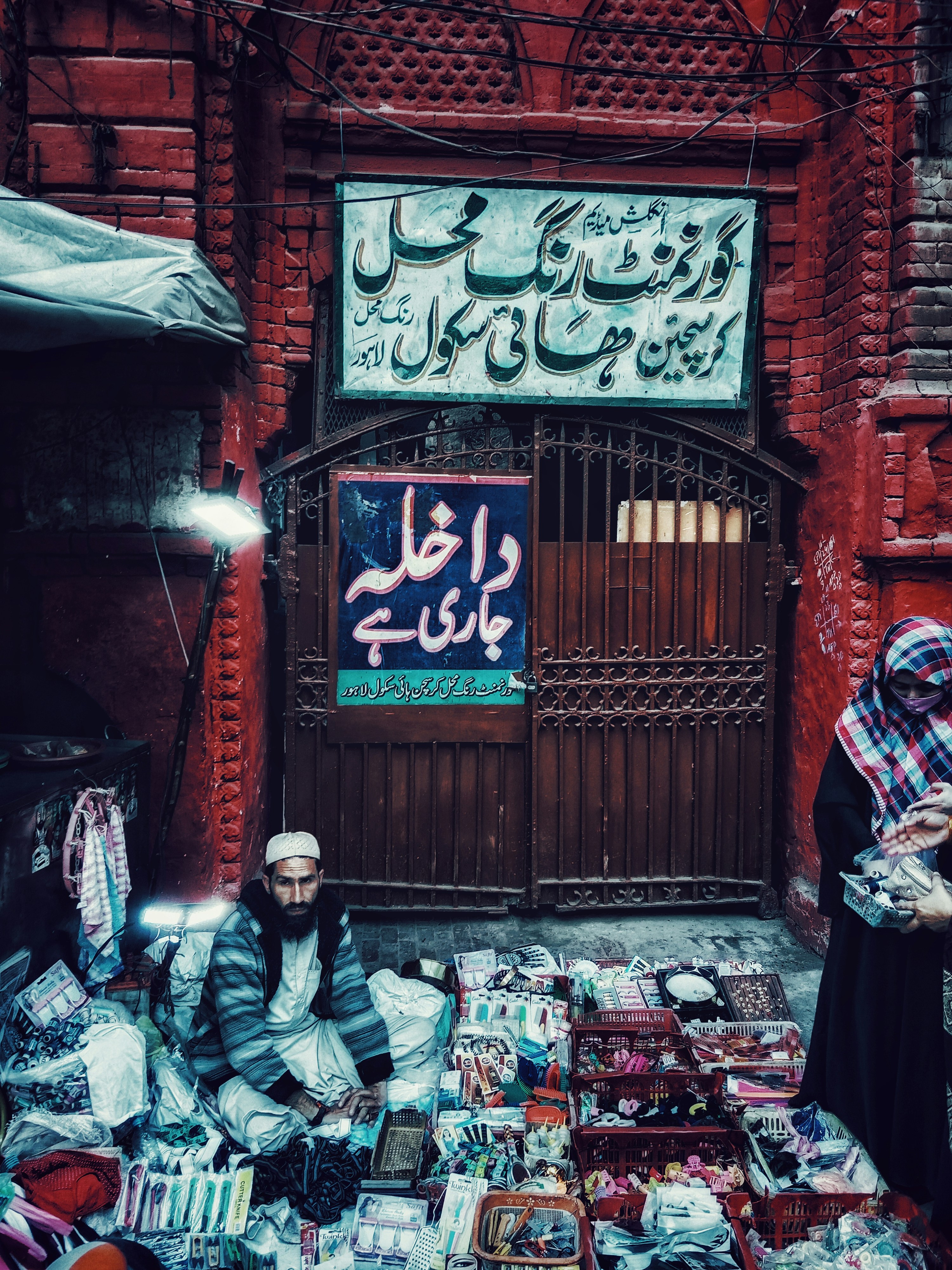 Brick-Arch Market Corner: vendor, wares, and signs under carved brickwork