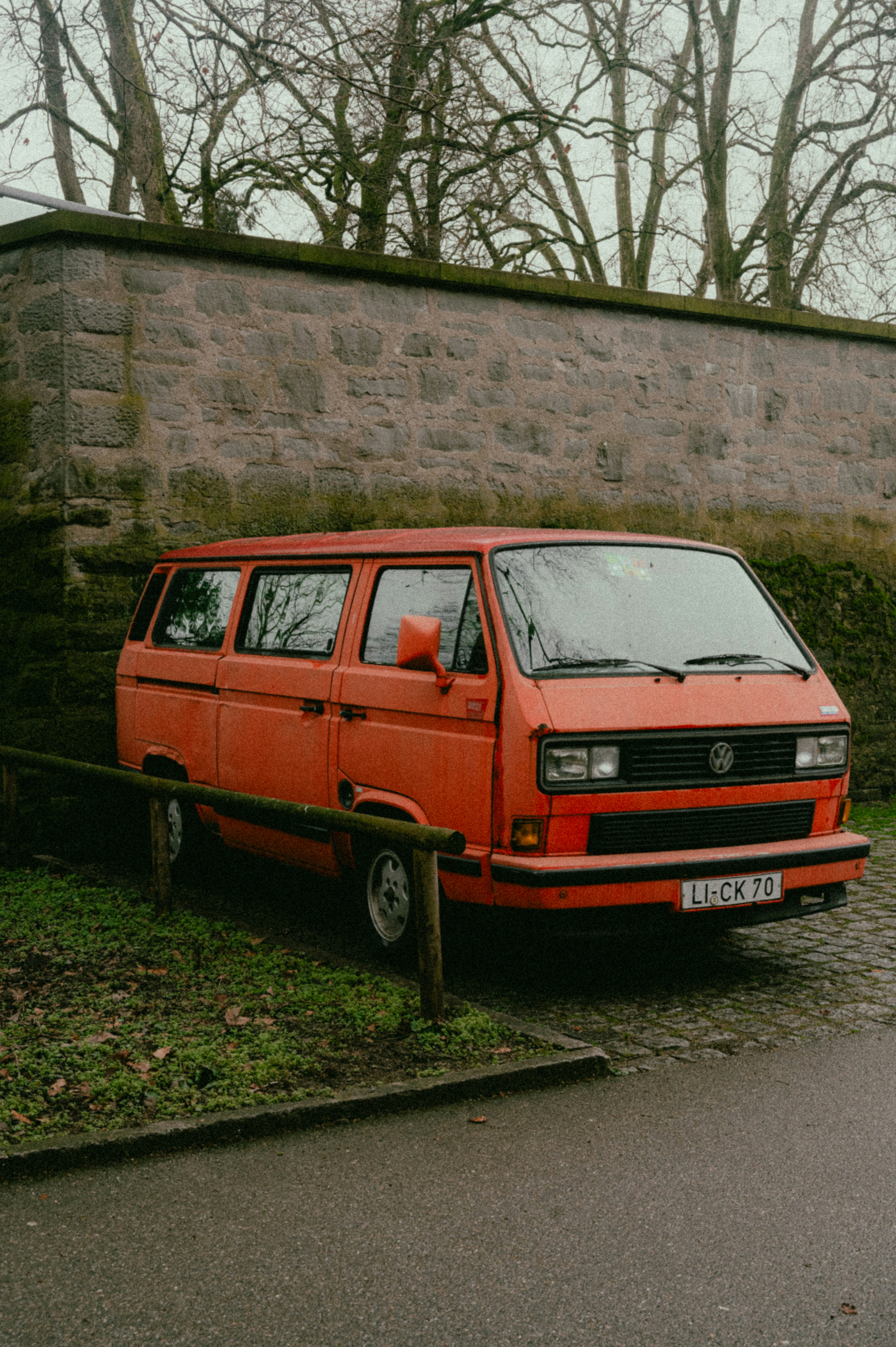 Rust-Orange VW Van Posed Against a Weathered Stone Wall