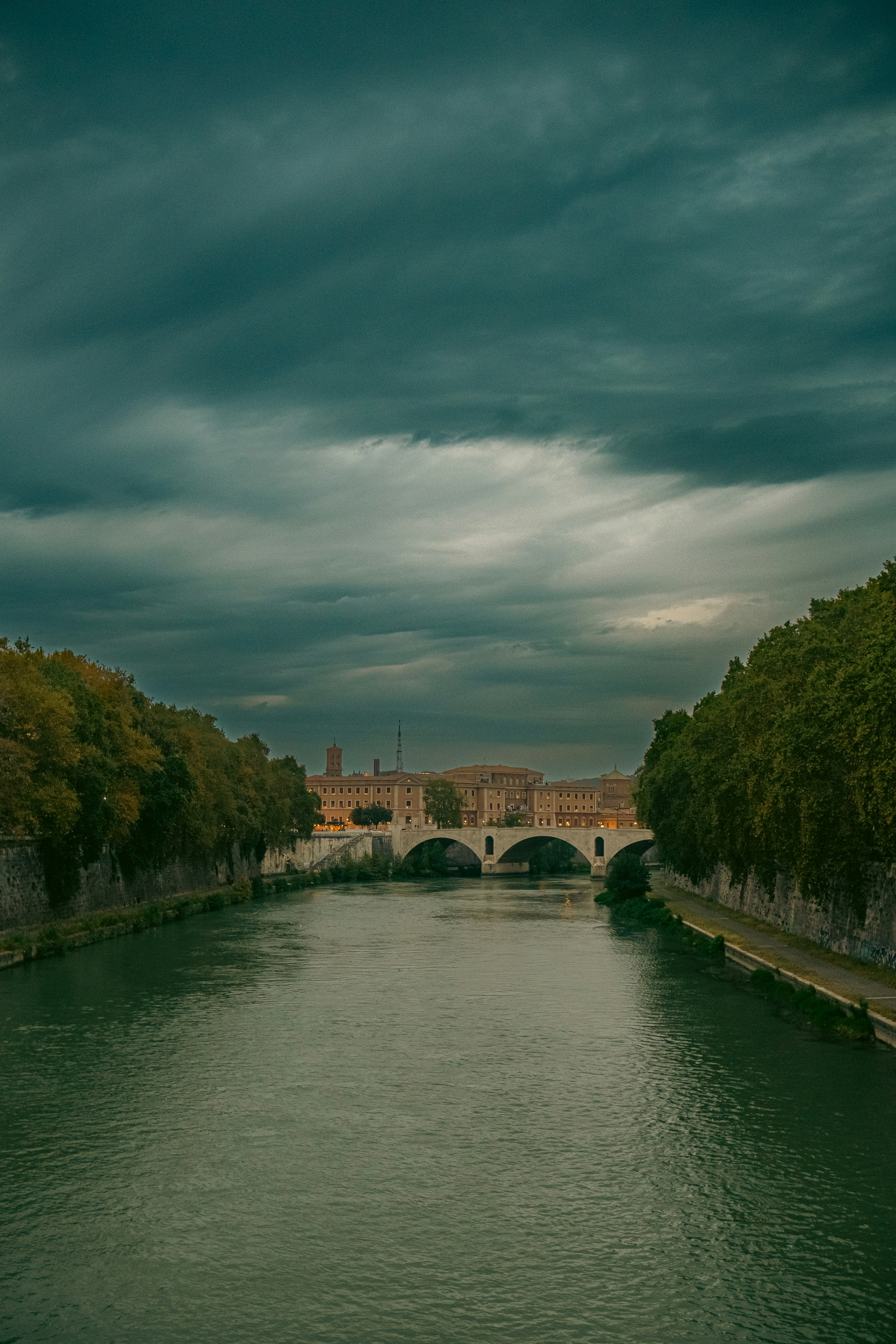 The Arc of Dusk: Stone Bridge Framing a River Under Stormy Skies