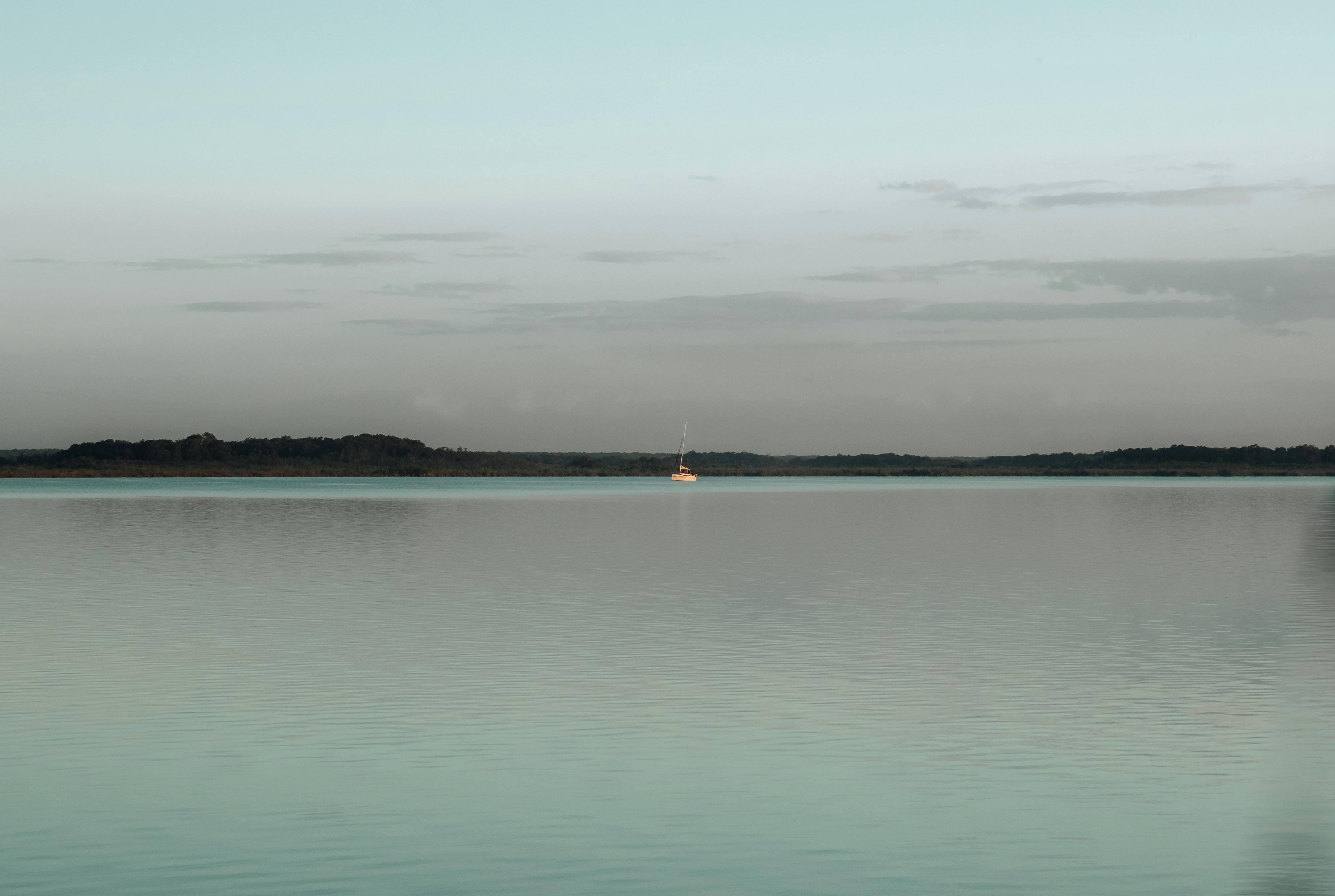  solitary sailboat on a glassy inlet at dusk