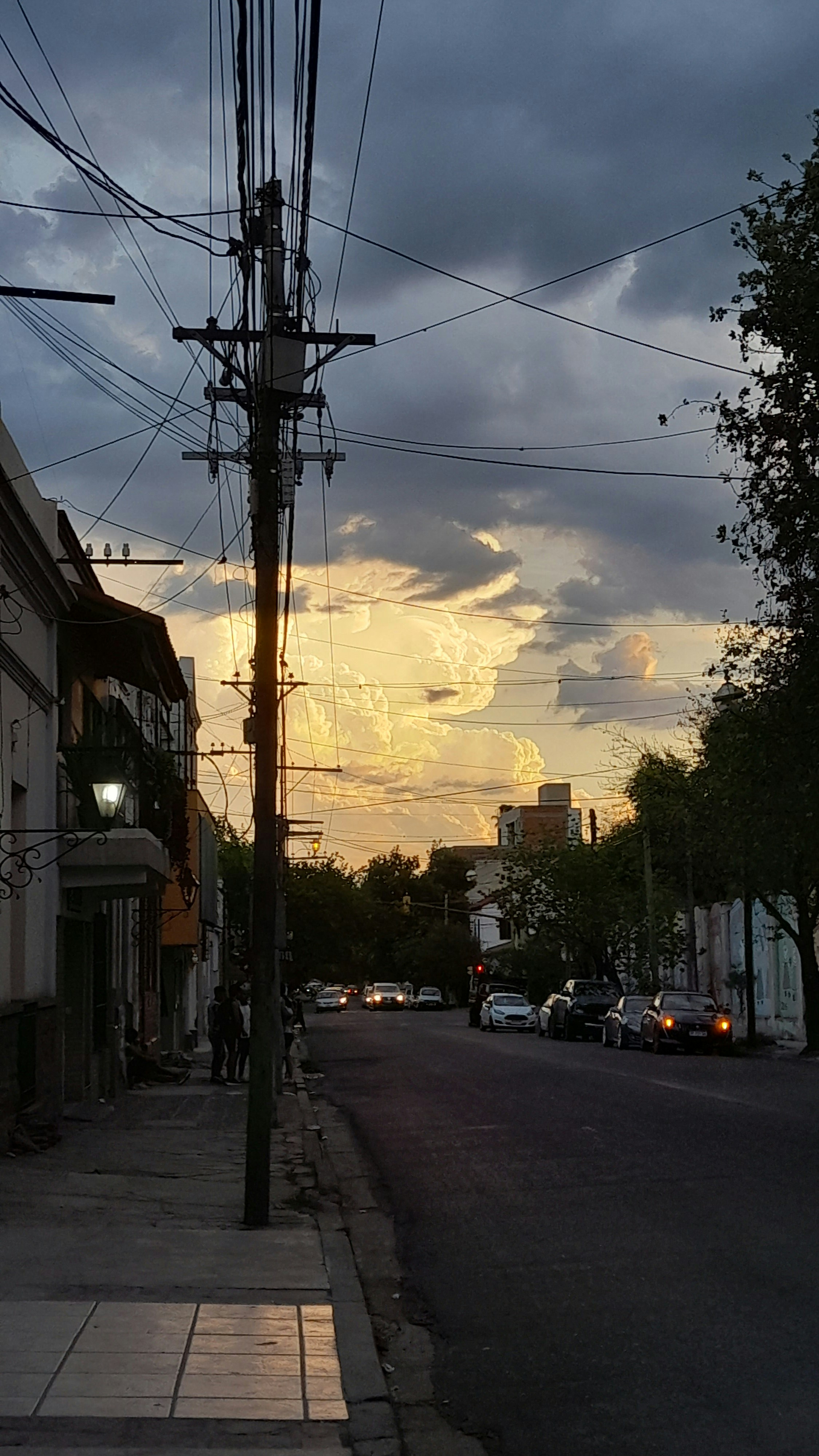Sunset glow over a quiet urban street under tangled power lines