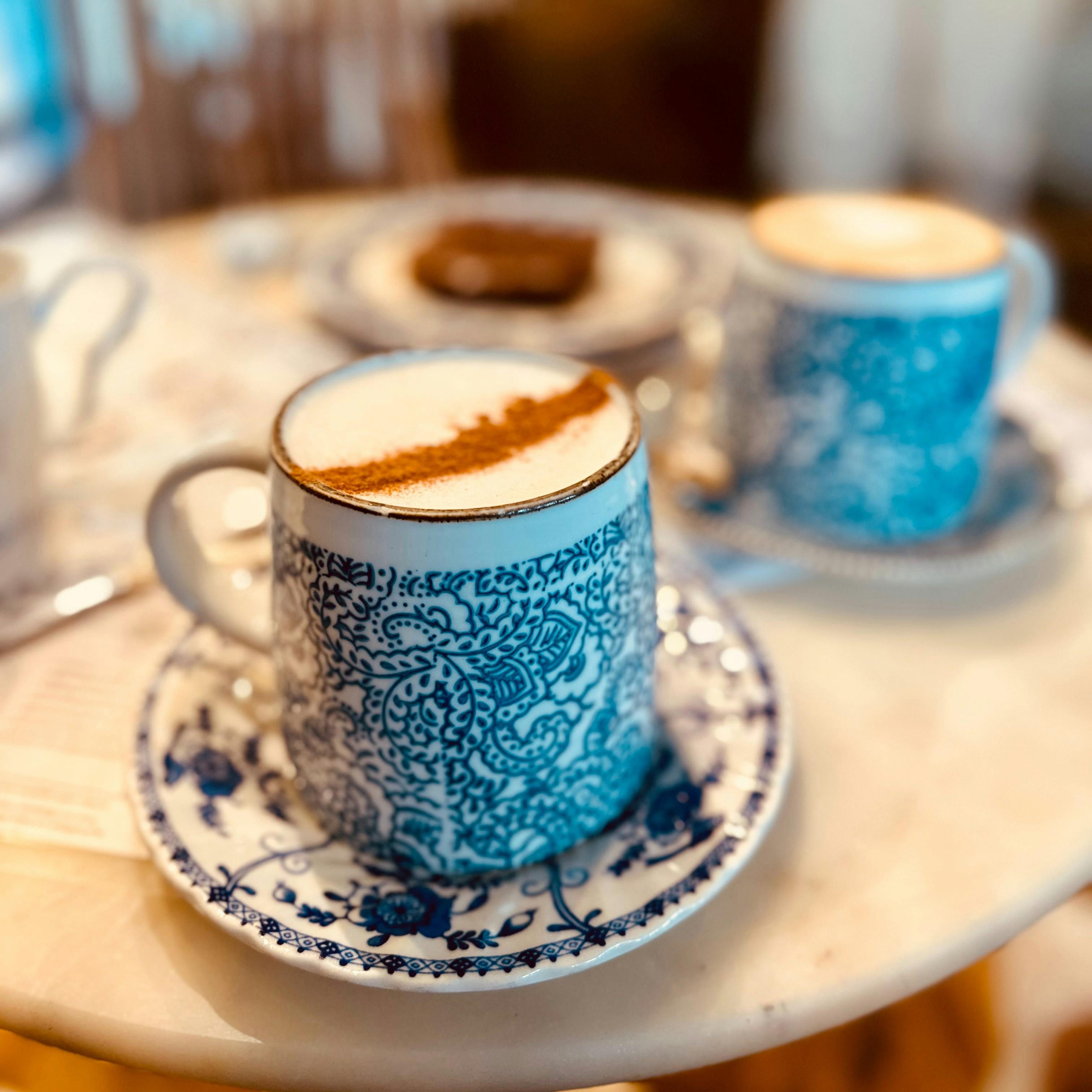 Cobalt Latte Focus: Foreground cup framed by blue porcelain blooms on marble