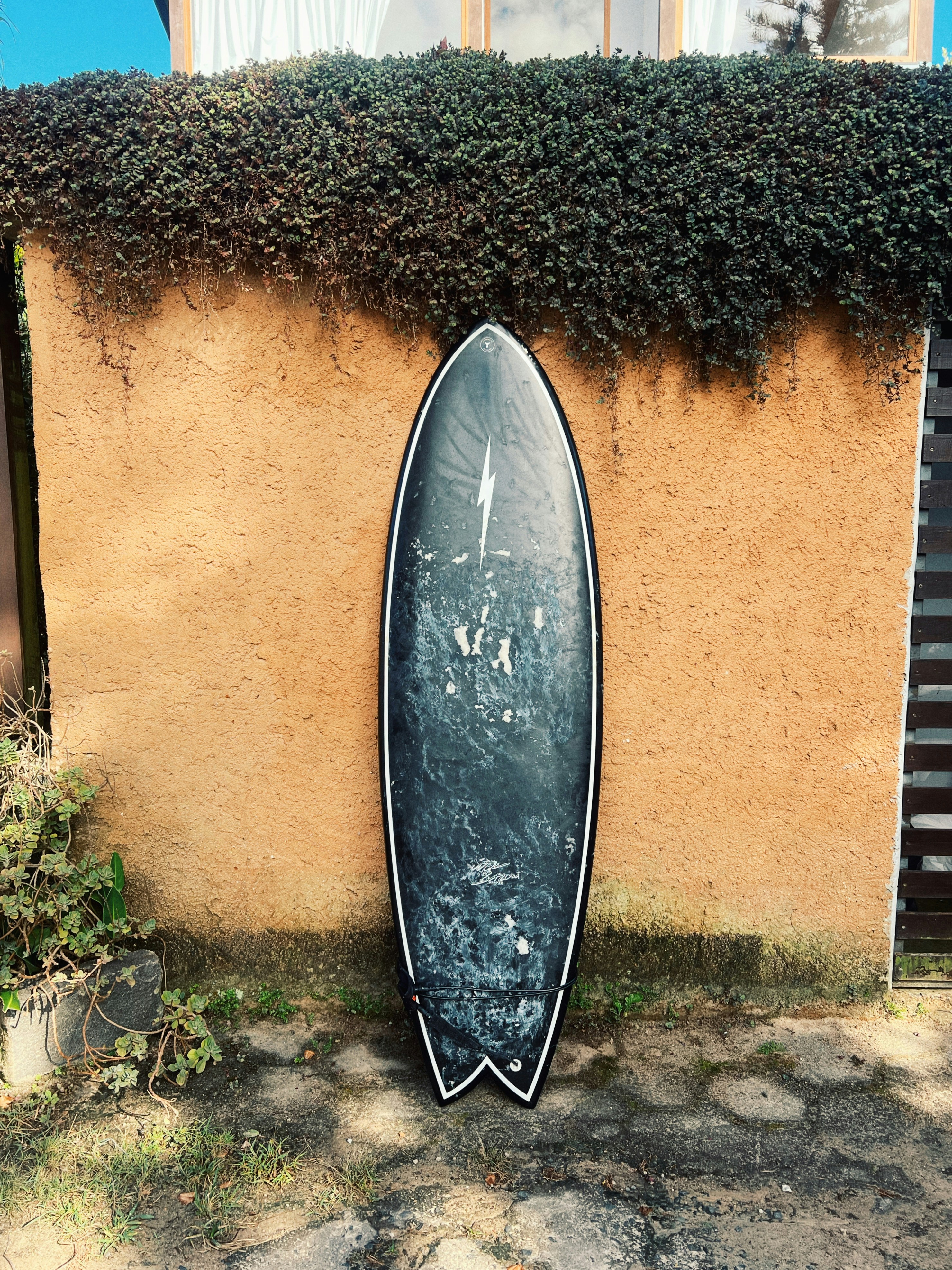 Solitary Surfboard Standing Tall Against a Sun-Warmed Wall