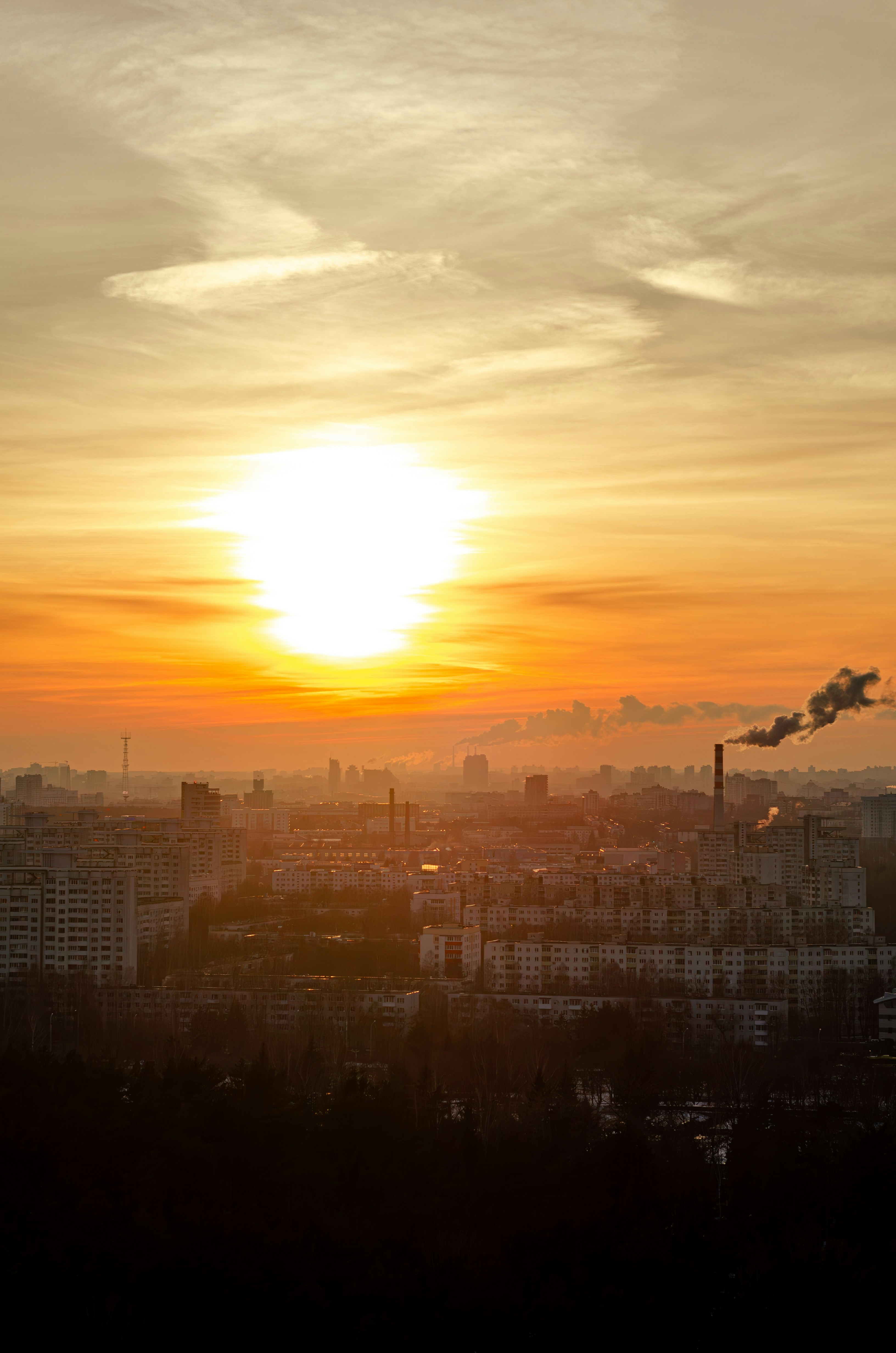 Embers on the Horizon: Sunset Over a Smoke-Stacked City