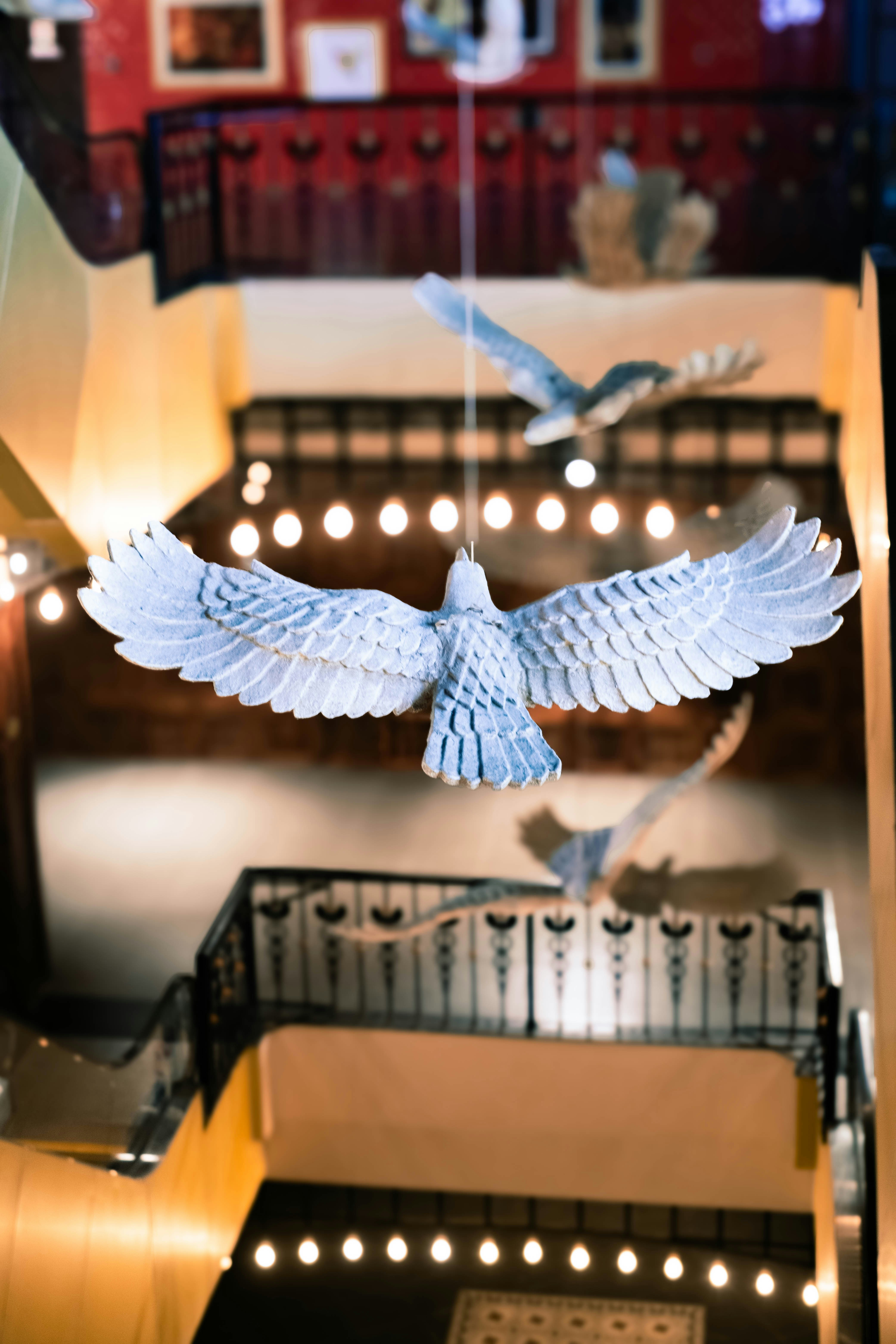 Winged White Owls Hover Above a Warm-Glow Staircase Atrium