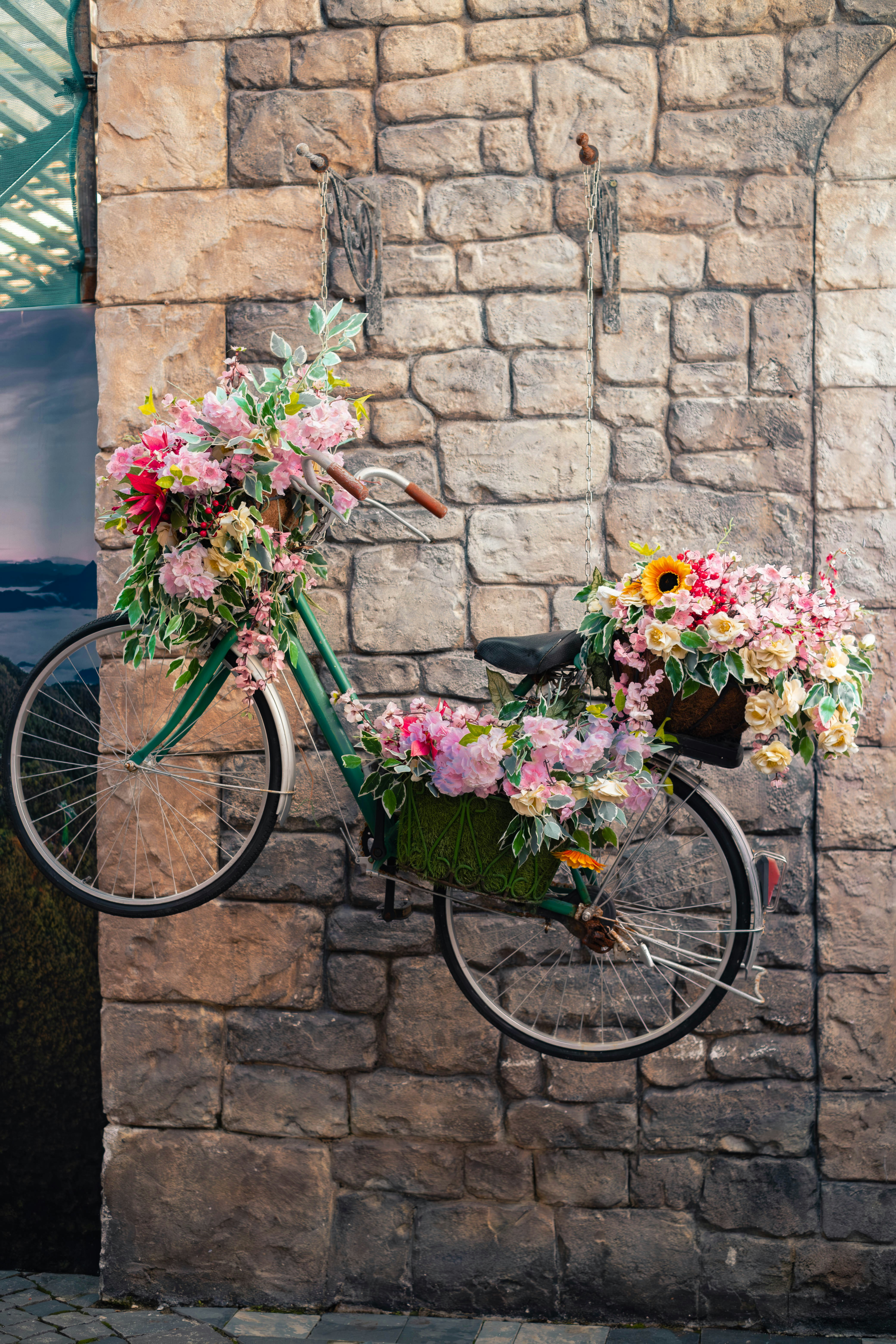 Blossoms on a Bicycle: A Flower-Laden Ride Against a Weathered Stone Wall