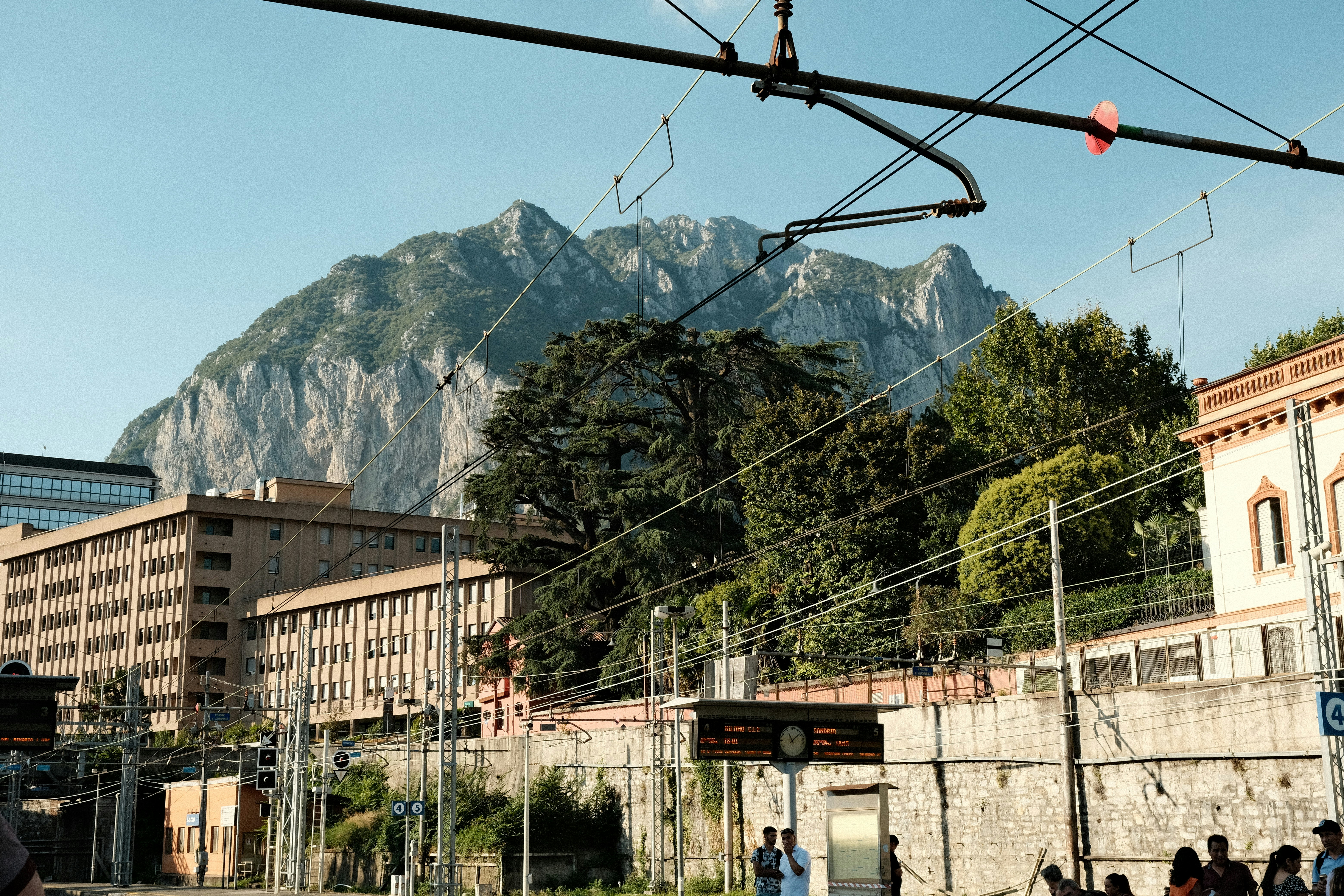 Peak Under Wires: Alpine Backdrop Framing a City Rail Yard