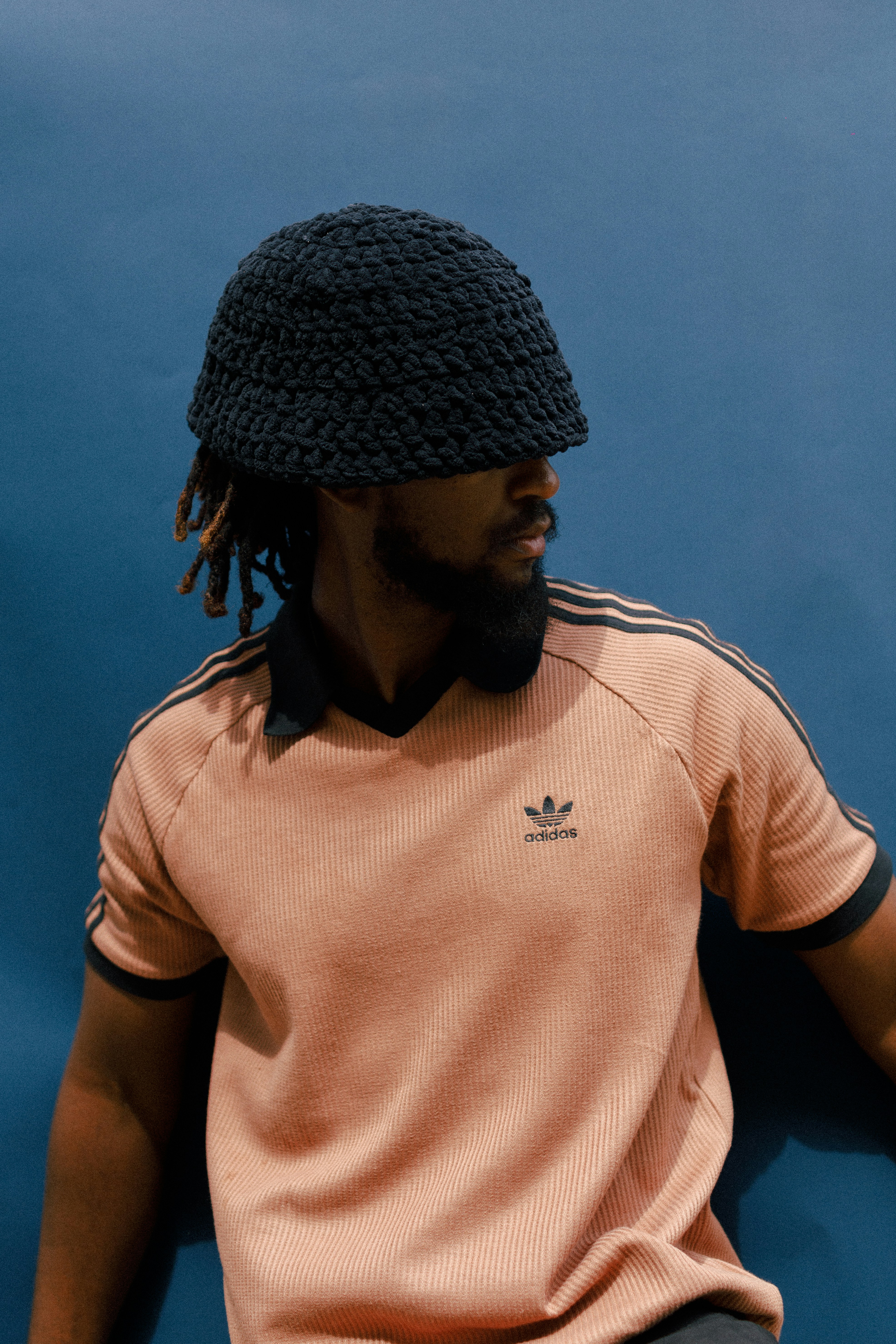 Profile in a Peach Polo: A Knit Hat Portrait Against a Blue Backdrop