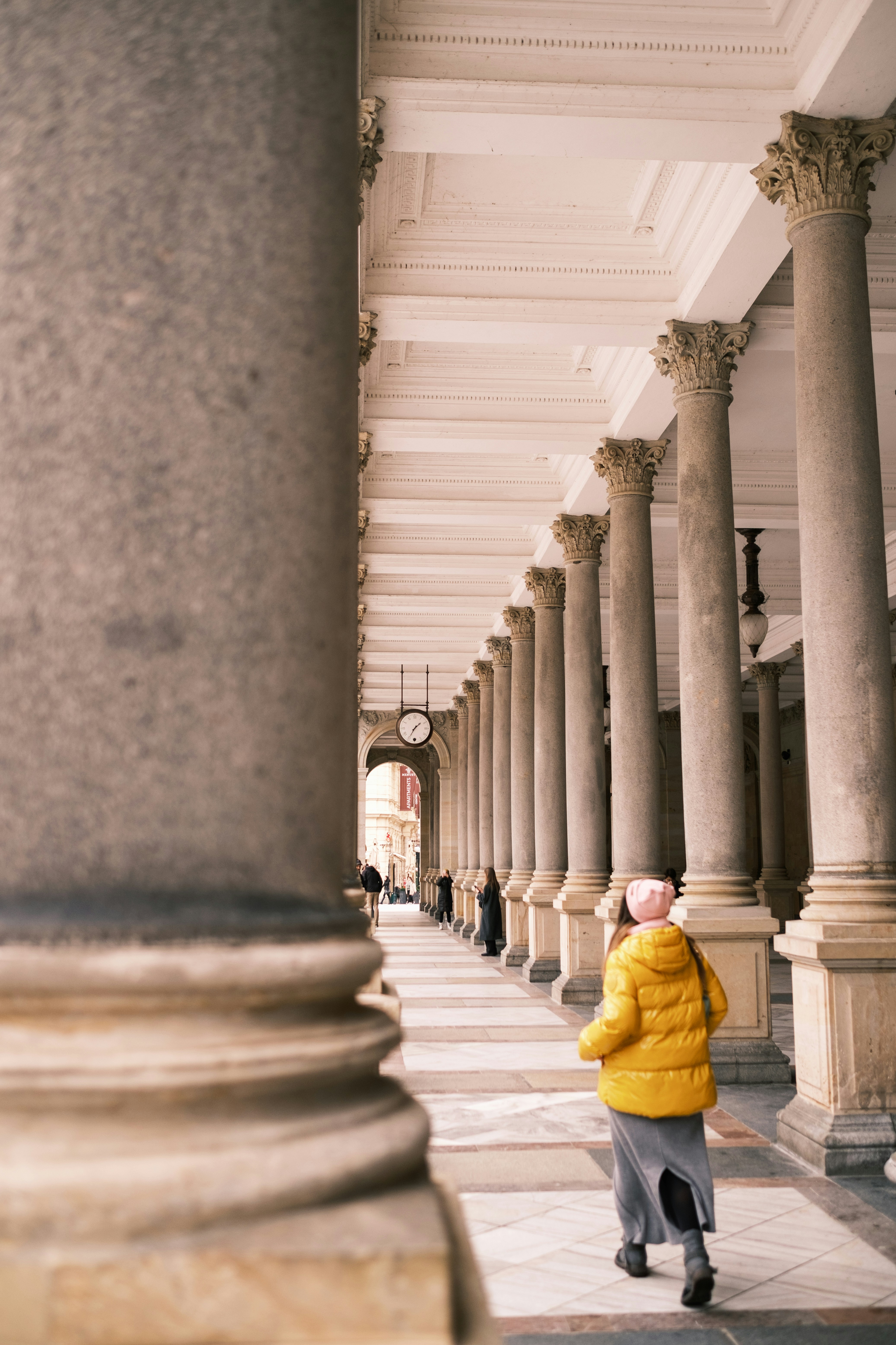 A person in a yellow jacket is walking down a walkway photo – Free ...