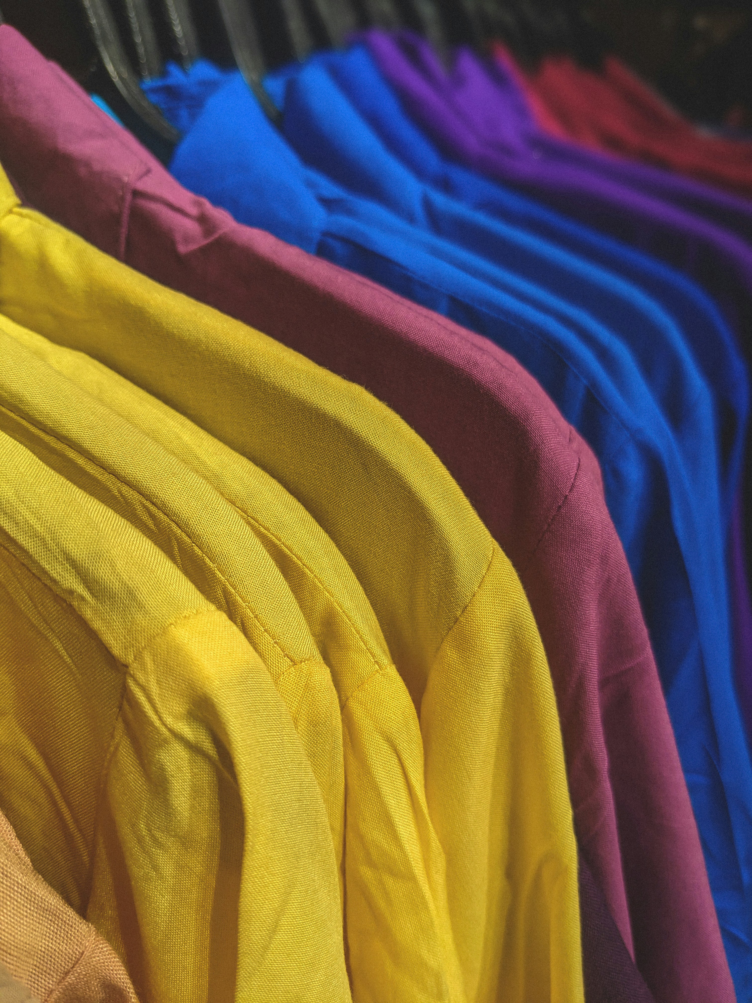 colorful cloths hanging. | a bunch of shirts that are on a rack