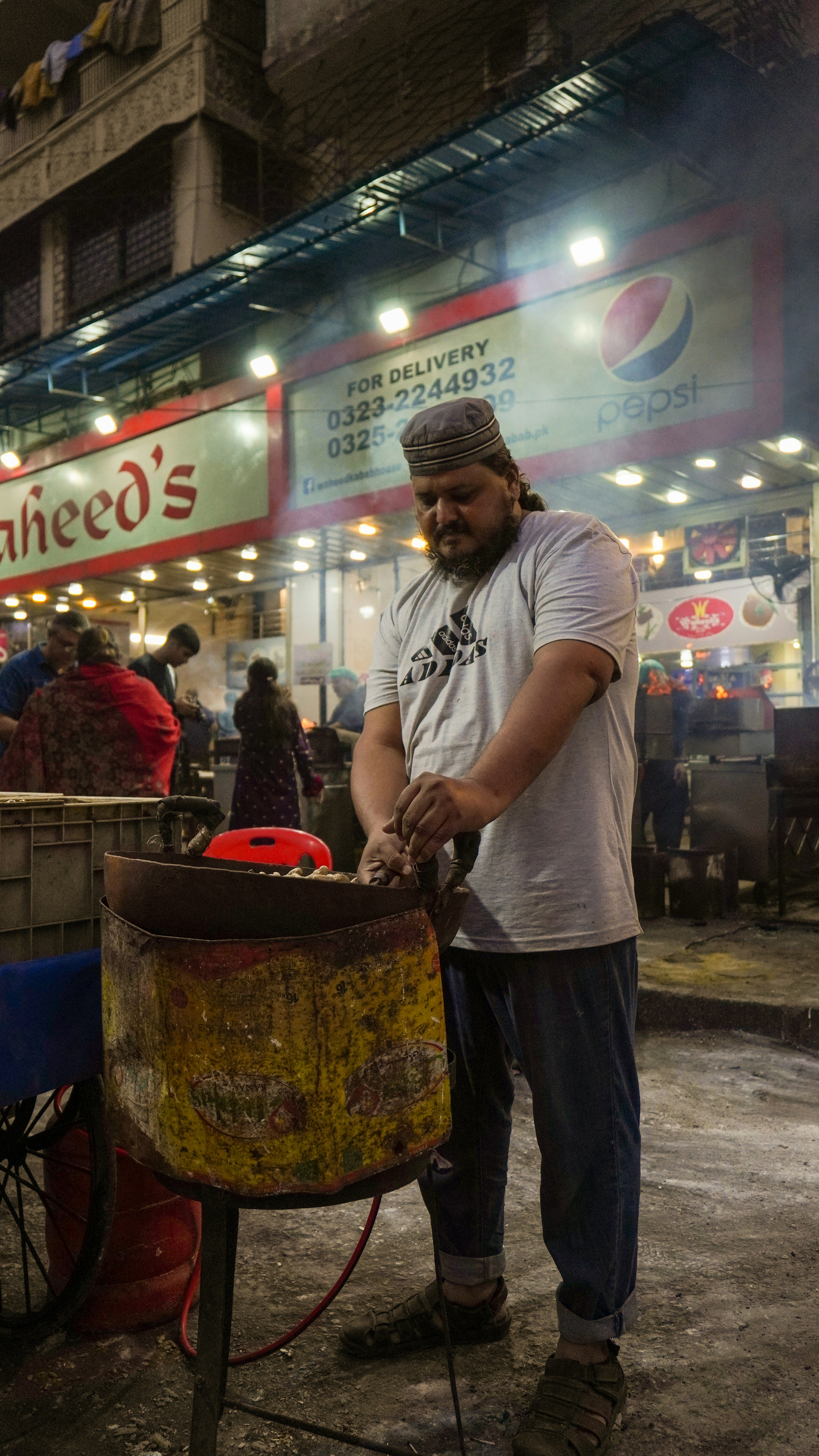 Butcher at the Flame: Street Vendor Grilling Under Neon Signs