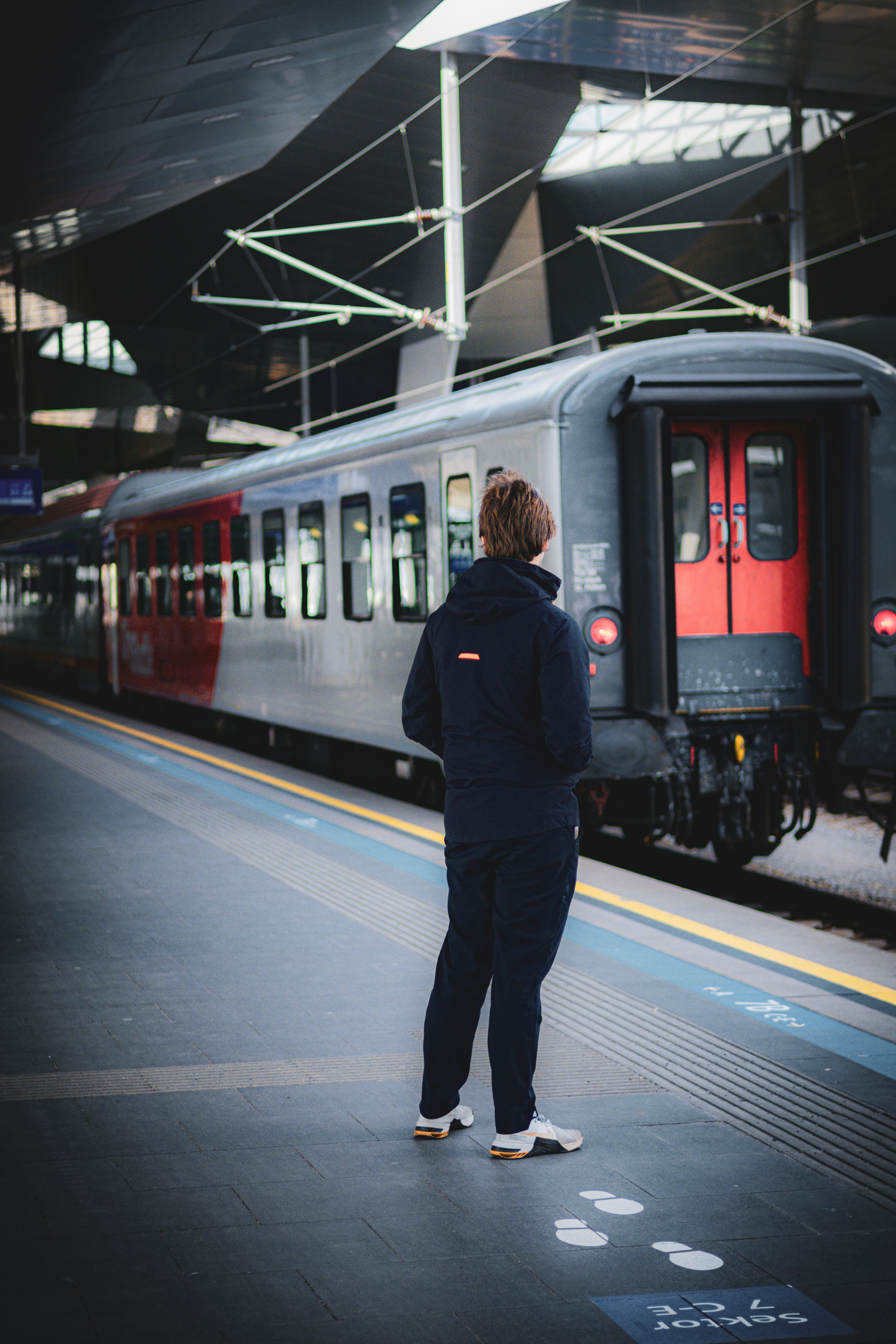 A person standing on a platform next to a train photo – Free Man Image ...