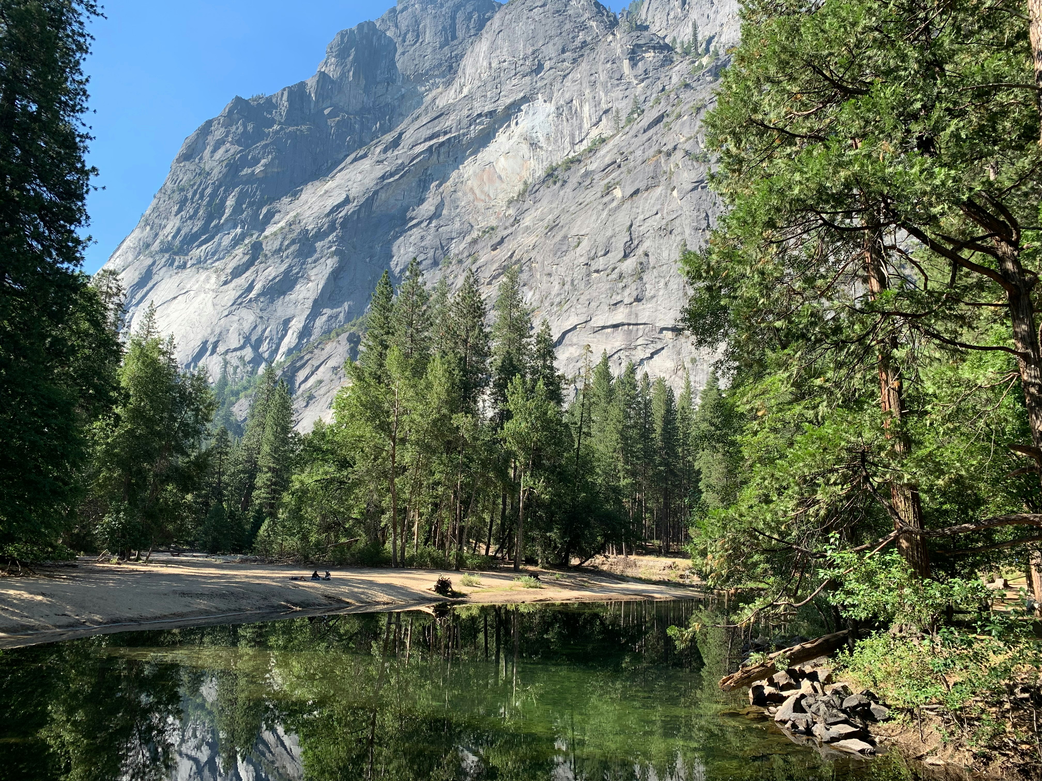 Towering cliff and lush forest reflected in a tranquil river.
